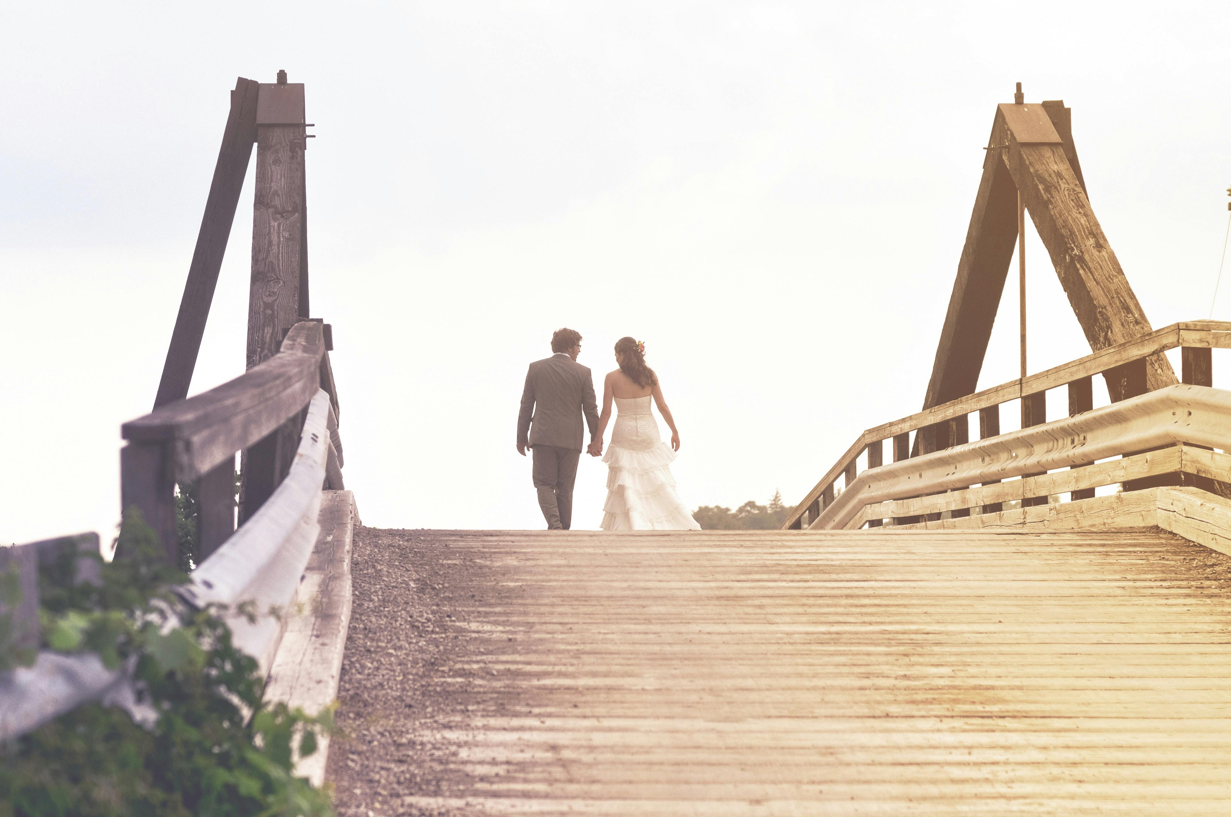Man and Woman Holding Hands While Walking on Bridge · Free Stock Photo