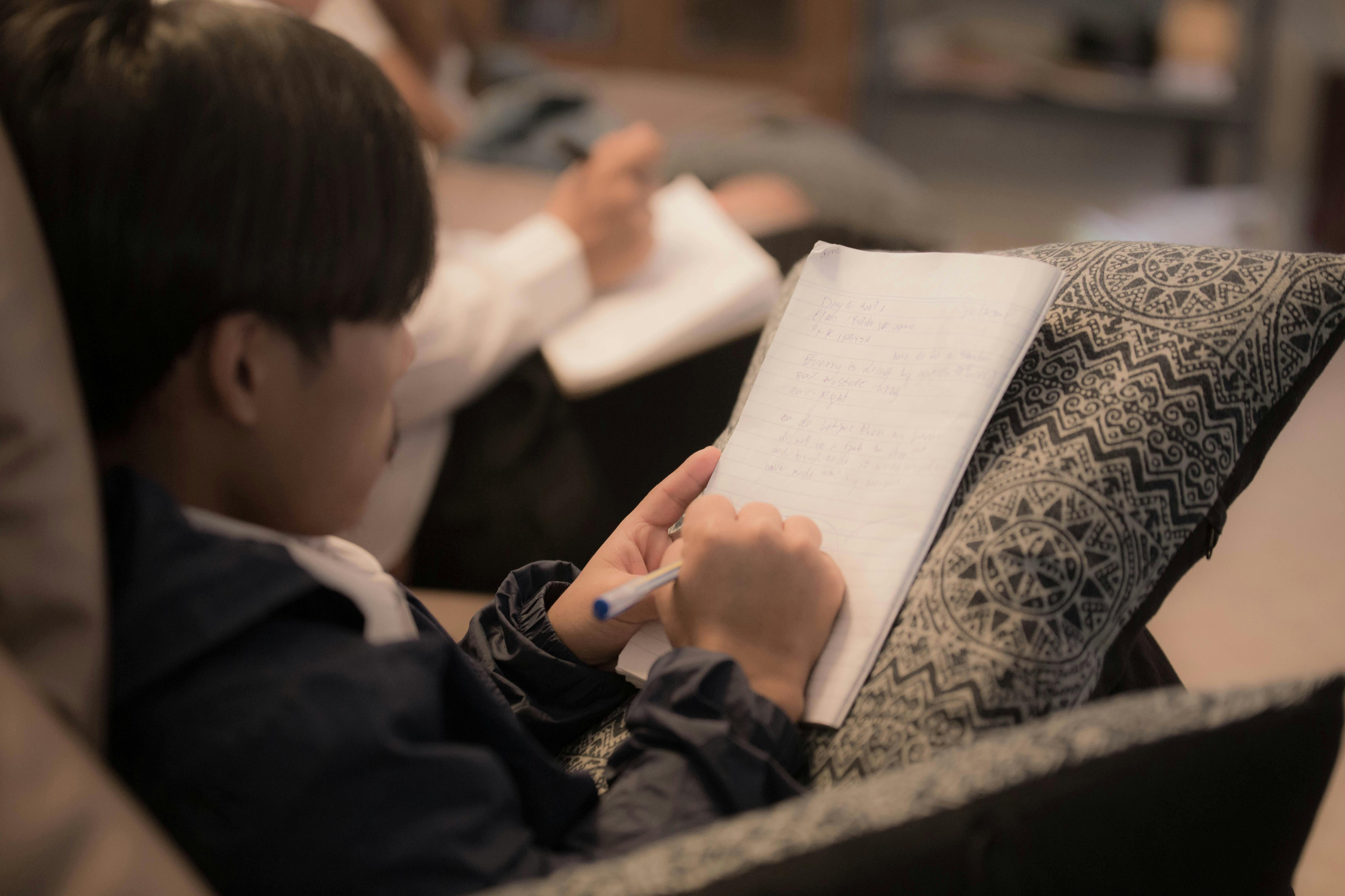 Person Holding Blue Ballpoint Pen Writing in Notebook · Free Stock Photo