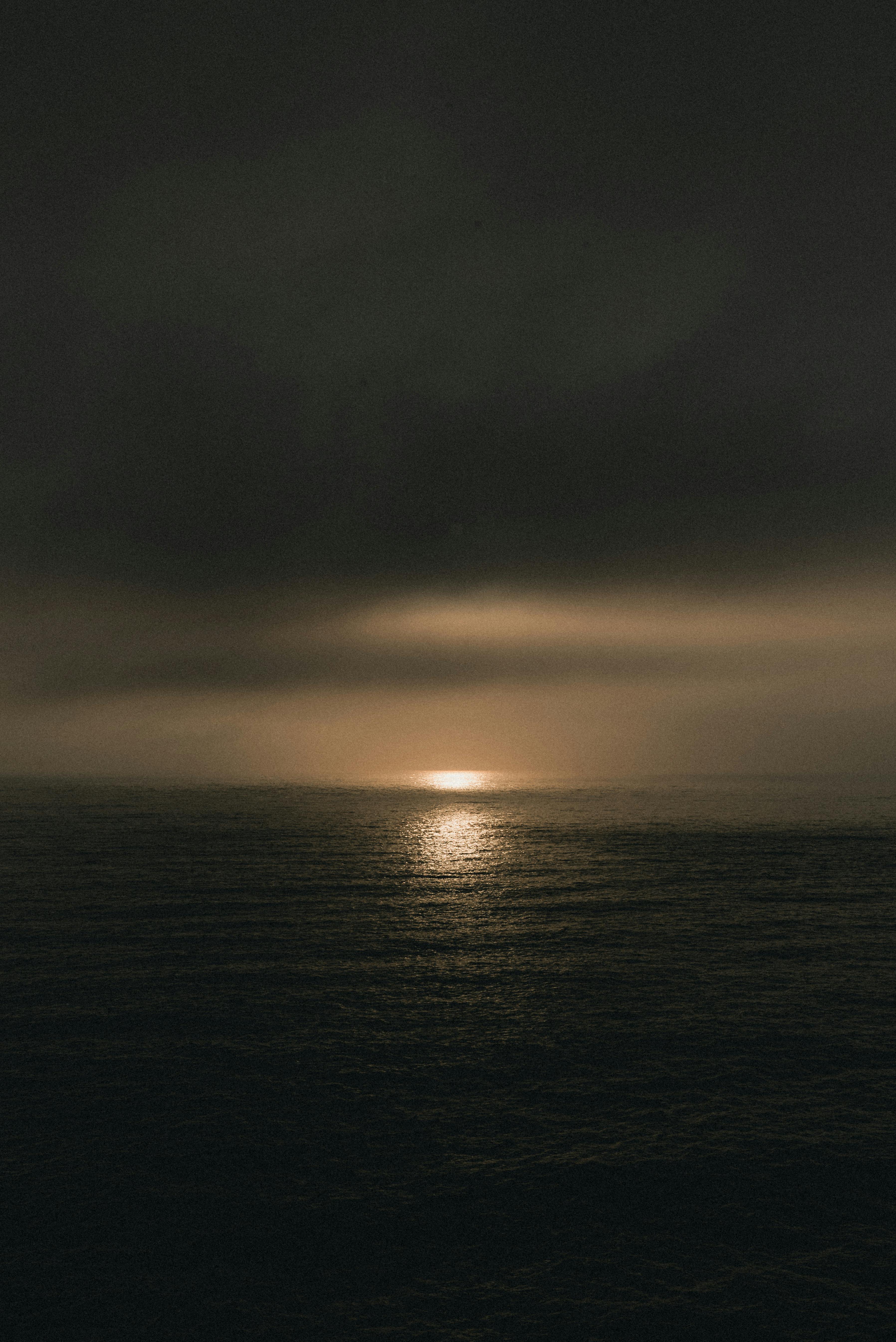 Setting Sun and Dark Sky Over a Sea · Free Stock Photo