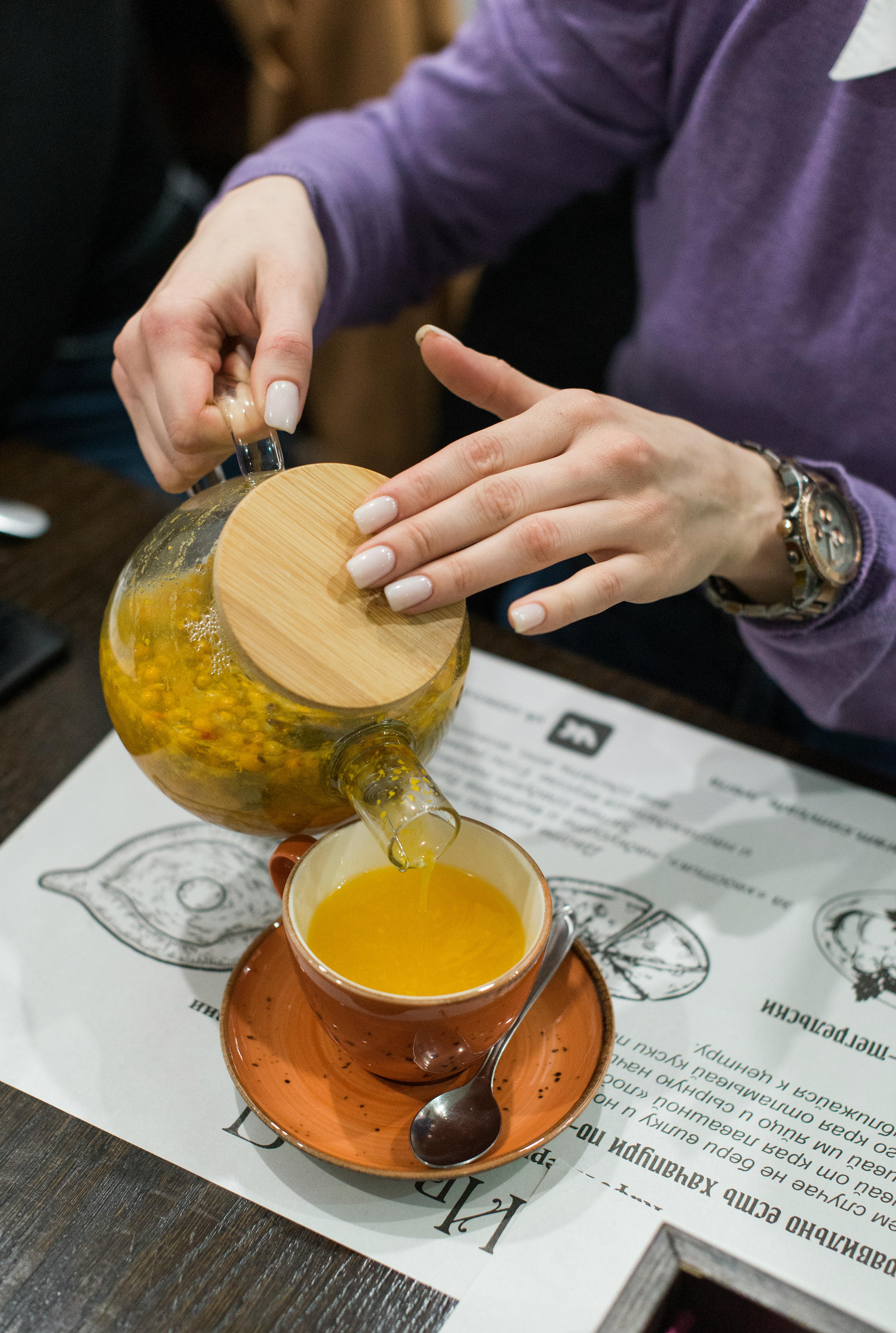 Woman Filling Tea in Cup on Table · Free Stock Photo