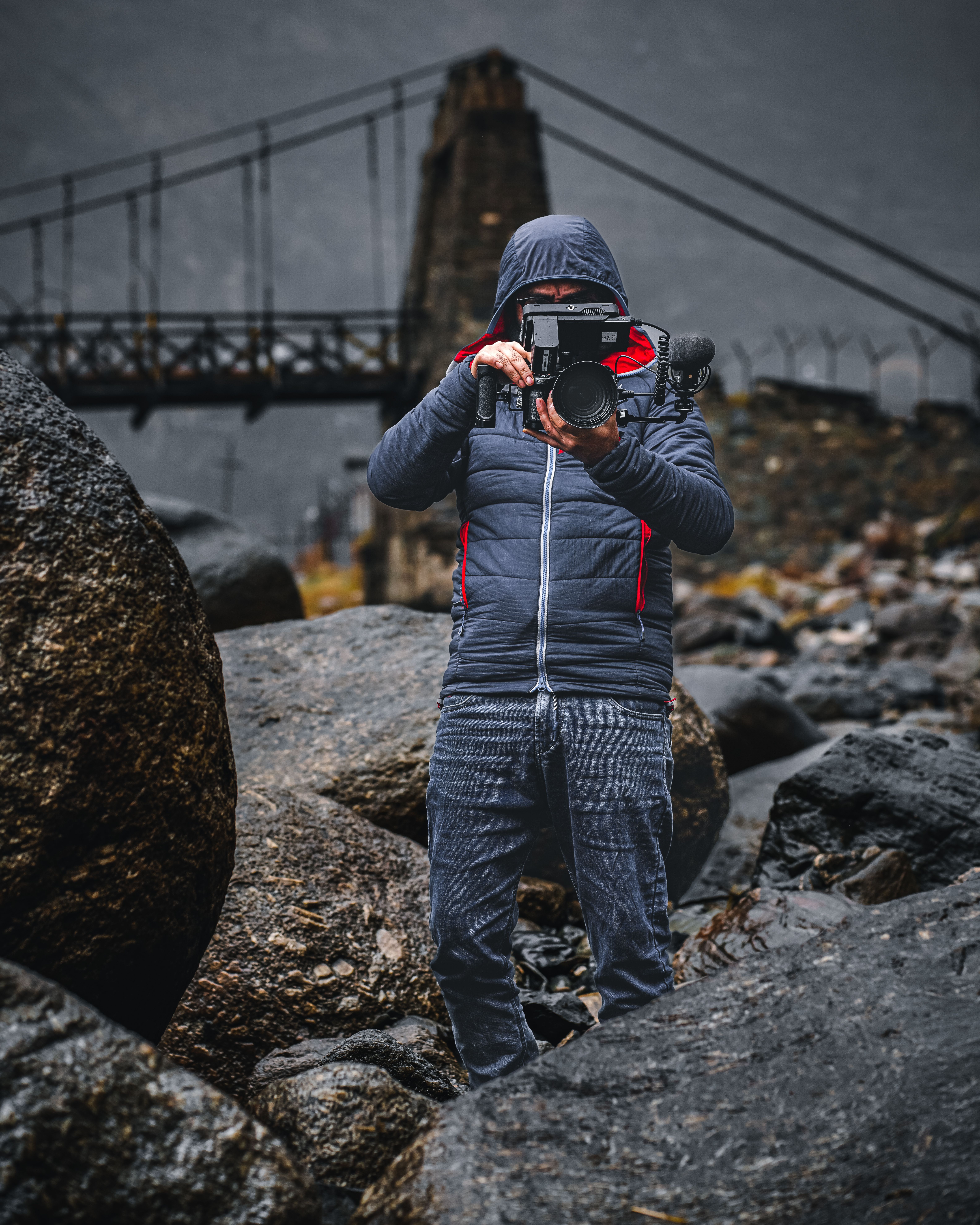A Man using a Video Camera while Standing on Rocks · Free Stock Photo