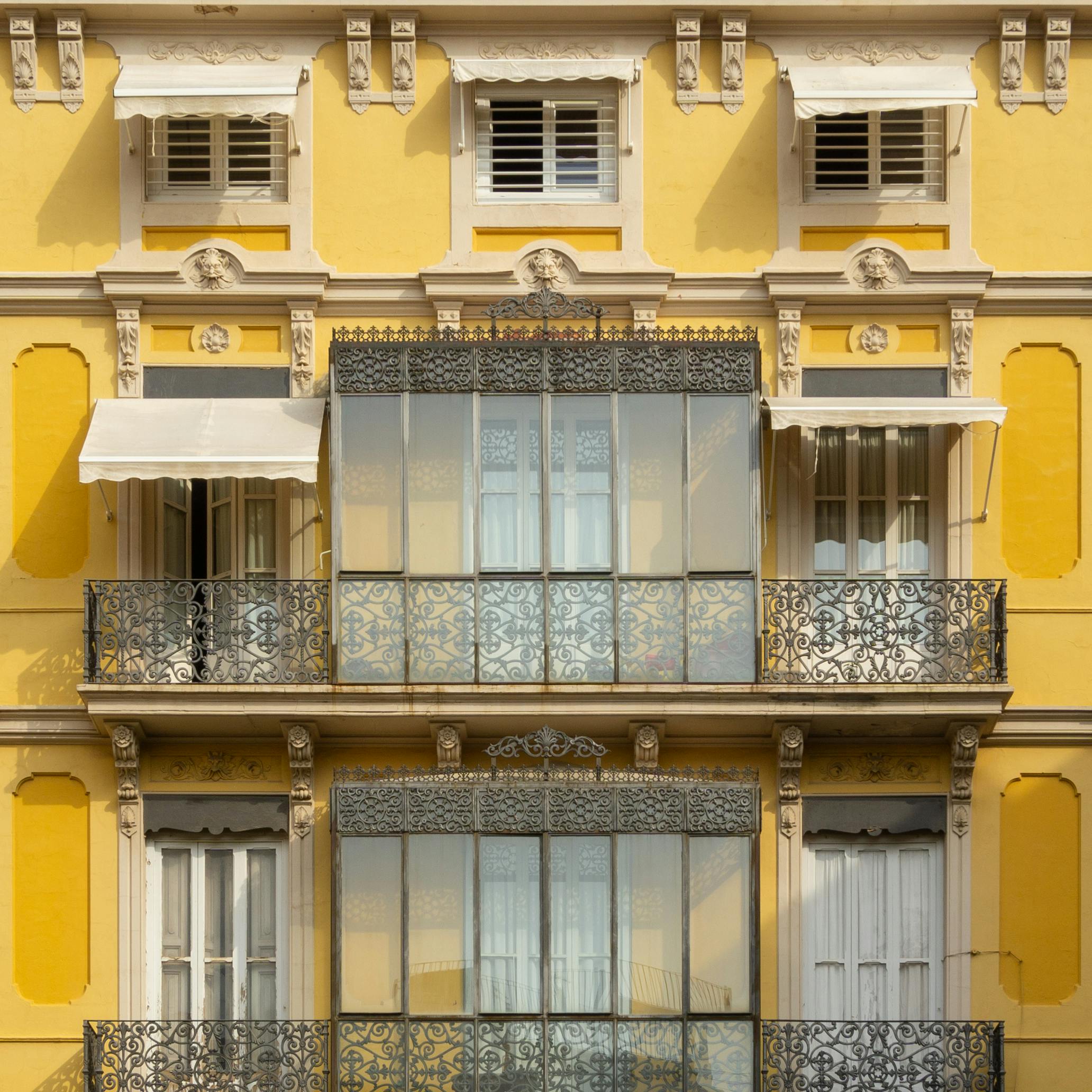 Yellow and White Concrete Building with Metal Railings and Canopies ...