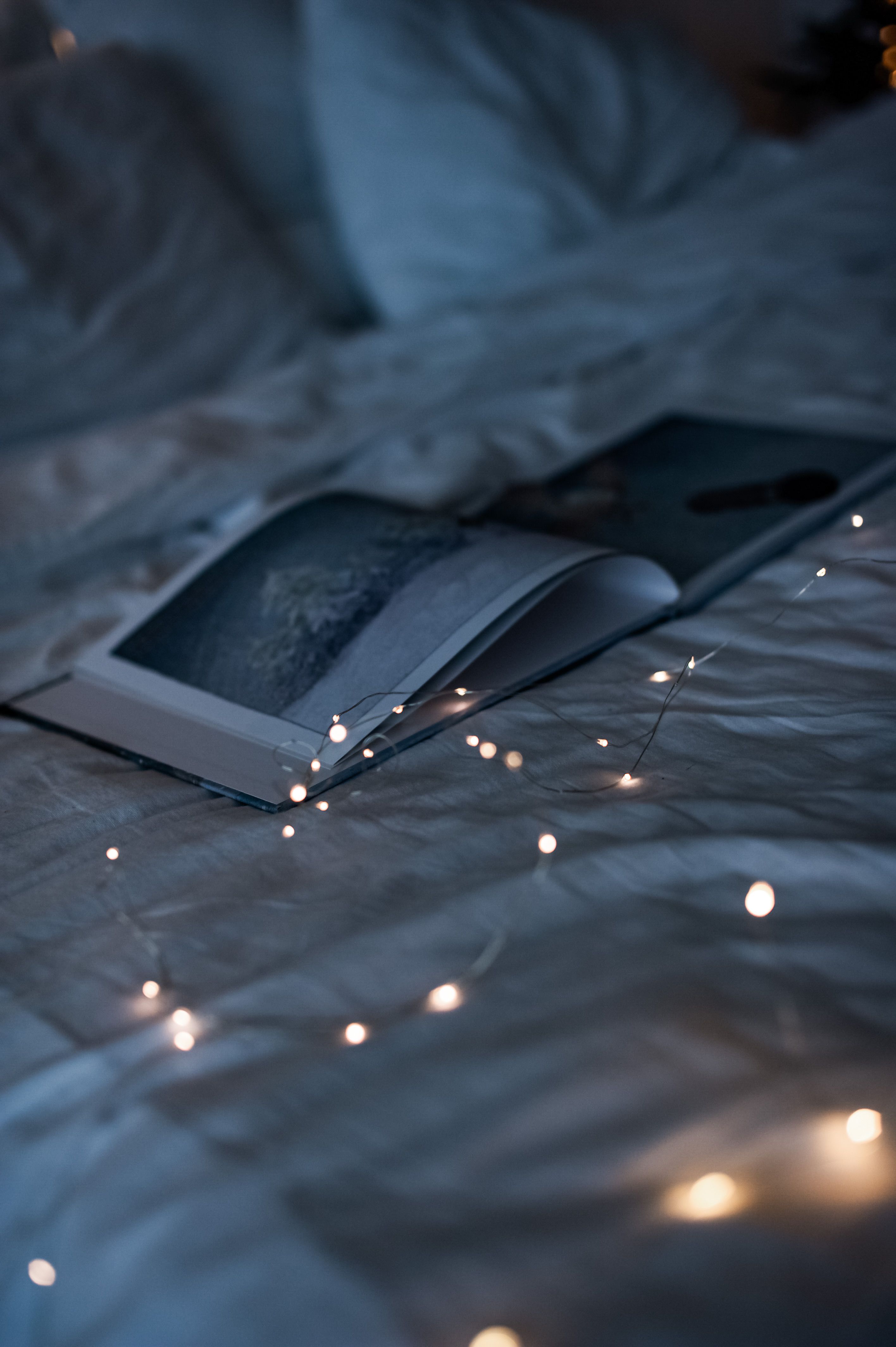 String Lights on Bed Beside a Book · Free Stock Photo