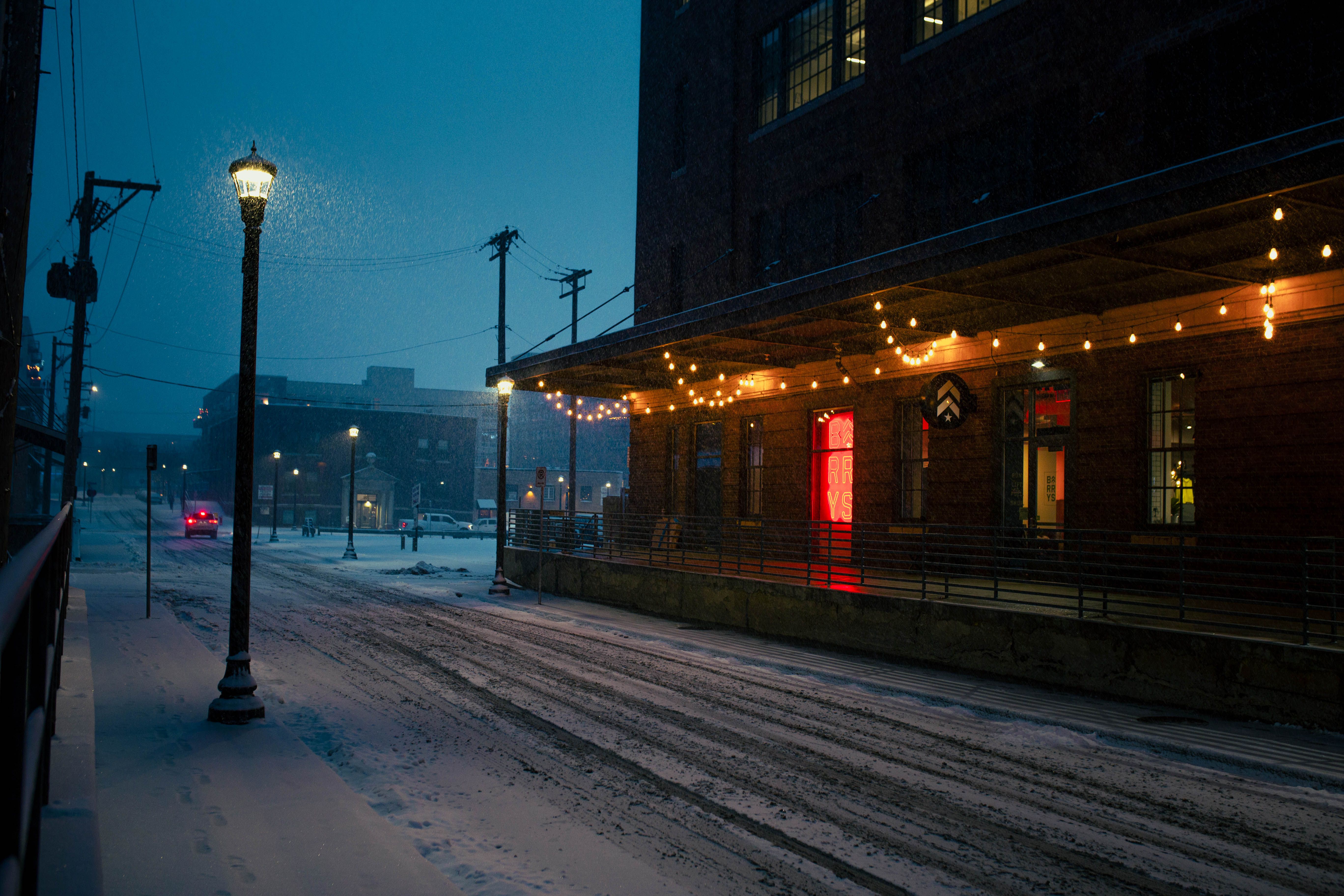 A Snow Covered Ground Near the Buildings on the Street at Night · Free ...