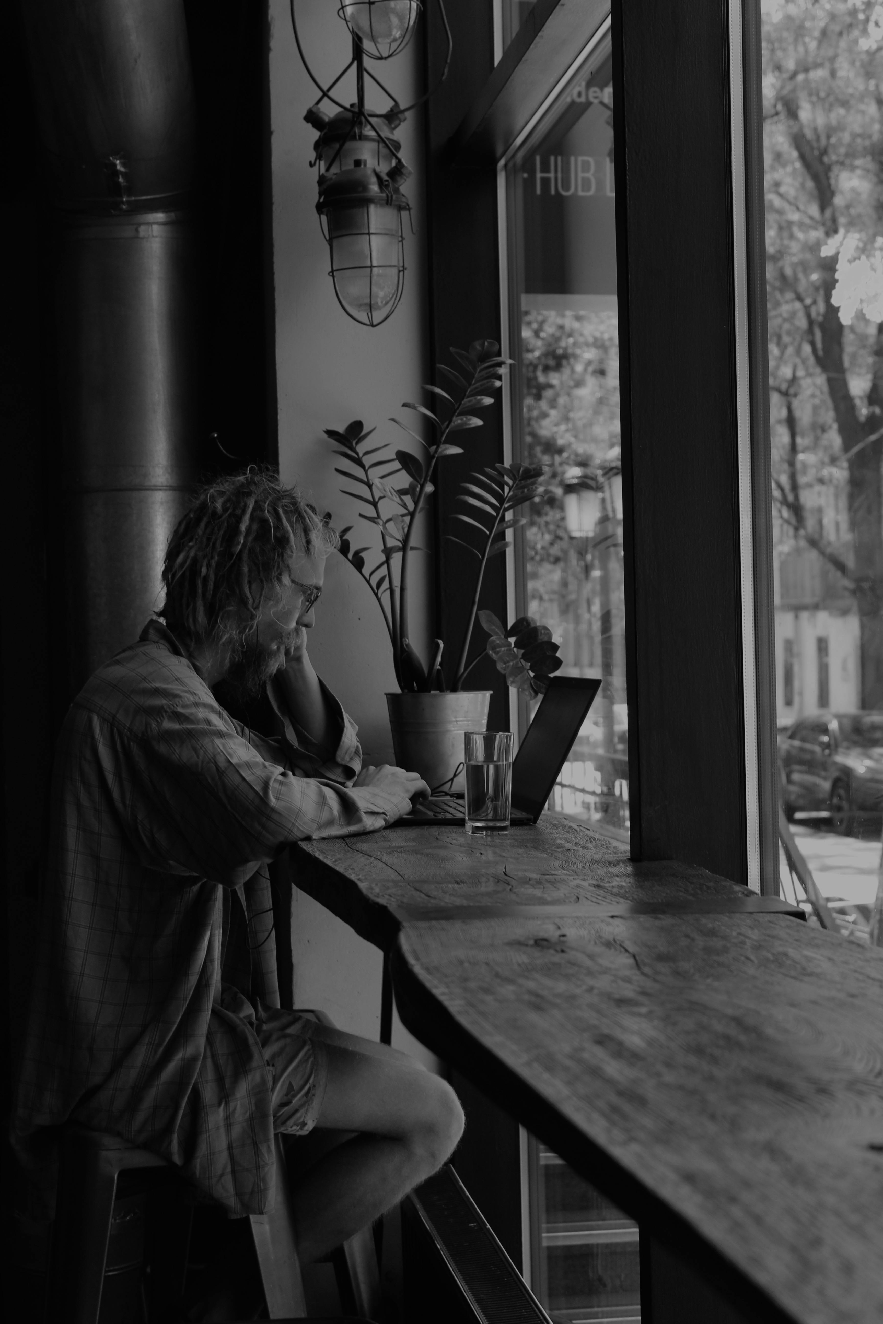 Grayscale Photo of Man using Laptop at a Counter Top · Free Stock Photo