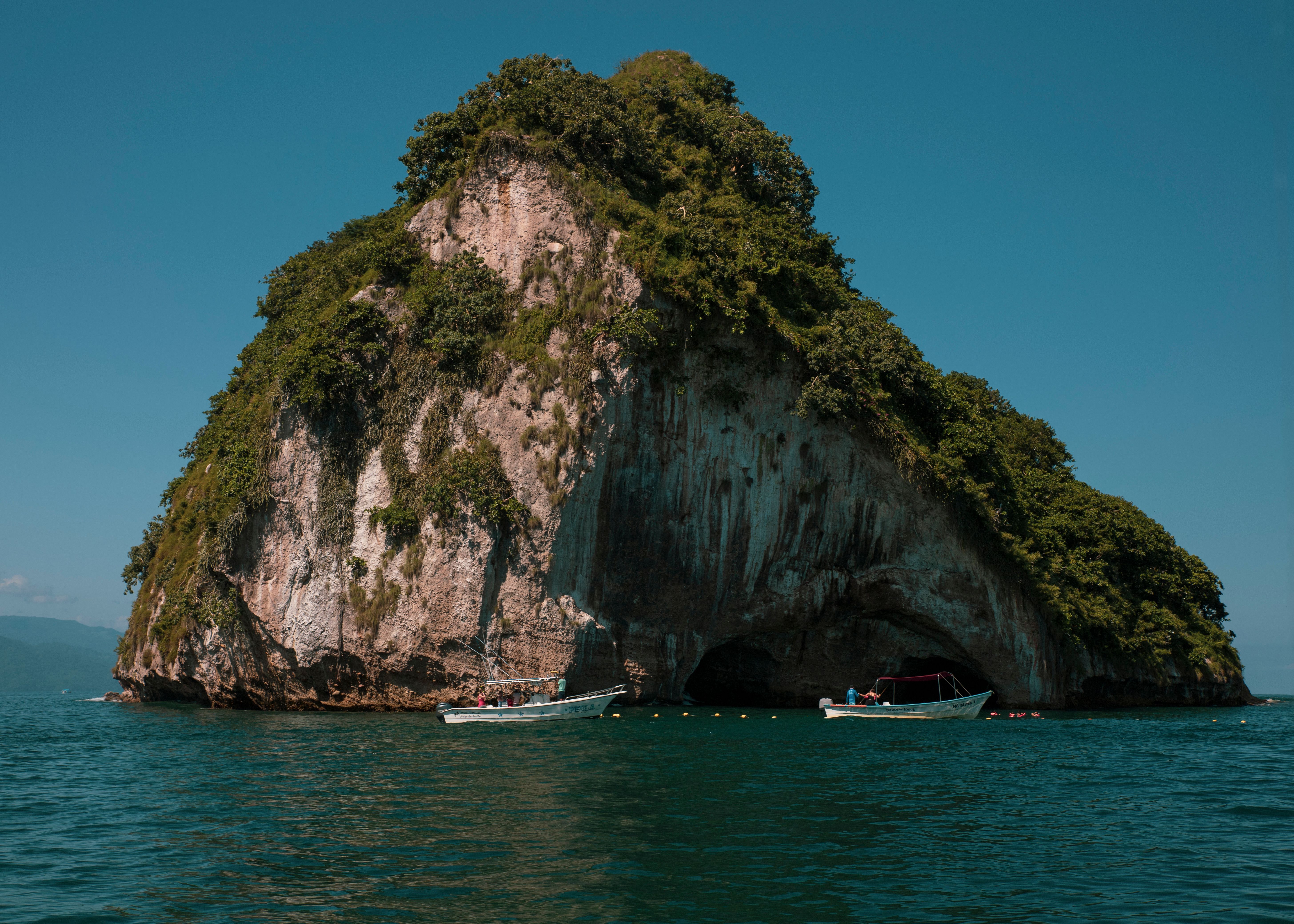 Fishing Boats Near Caves on an Island · Free Stock Photo