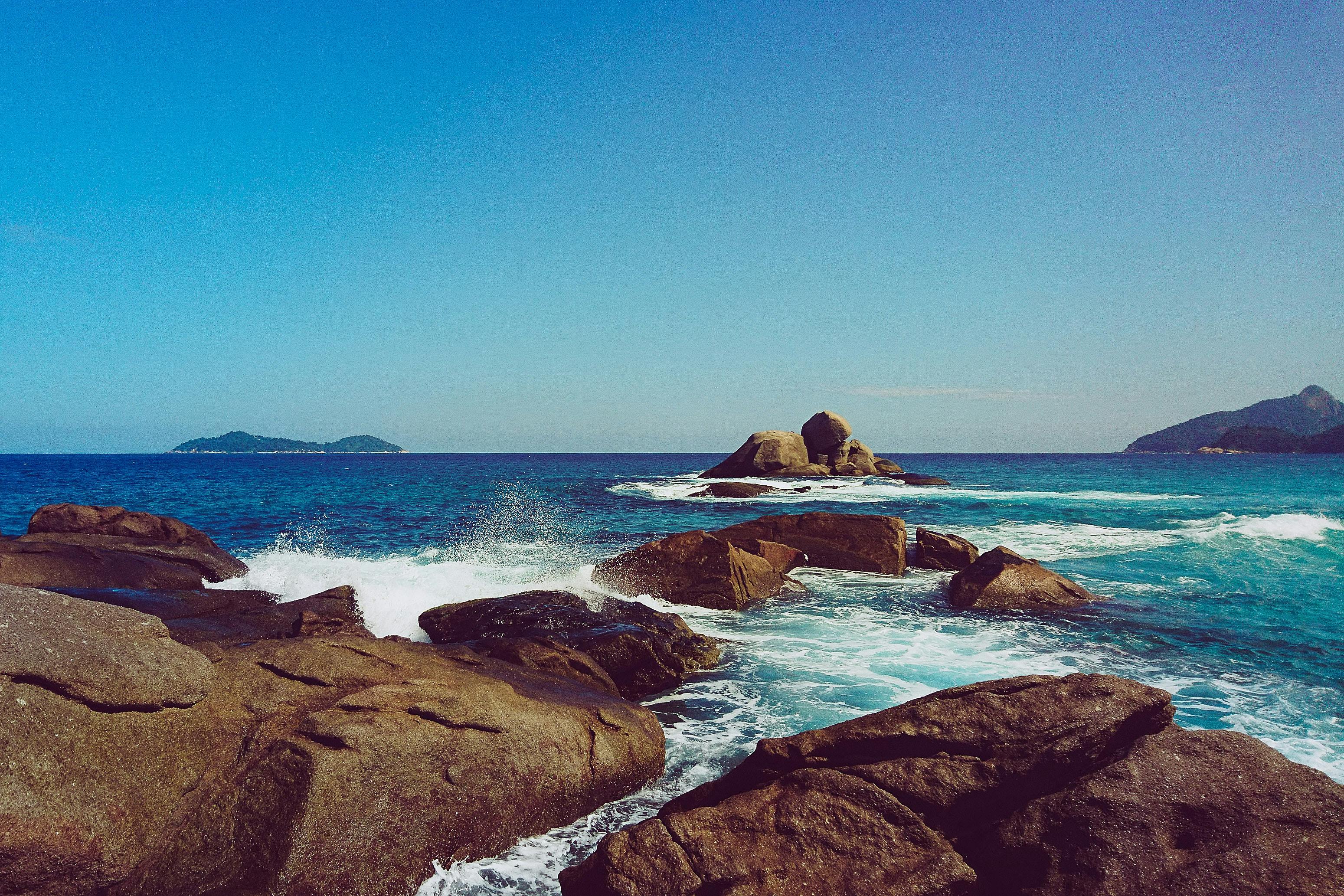 Brown Rock Formations on Sea Under the Blue Sky · Free Stock Photo