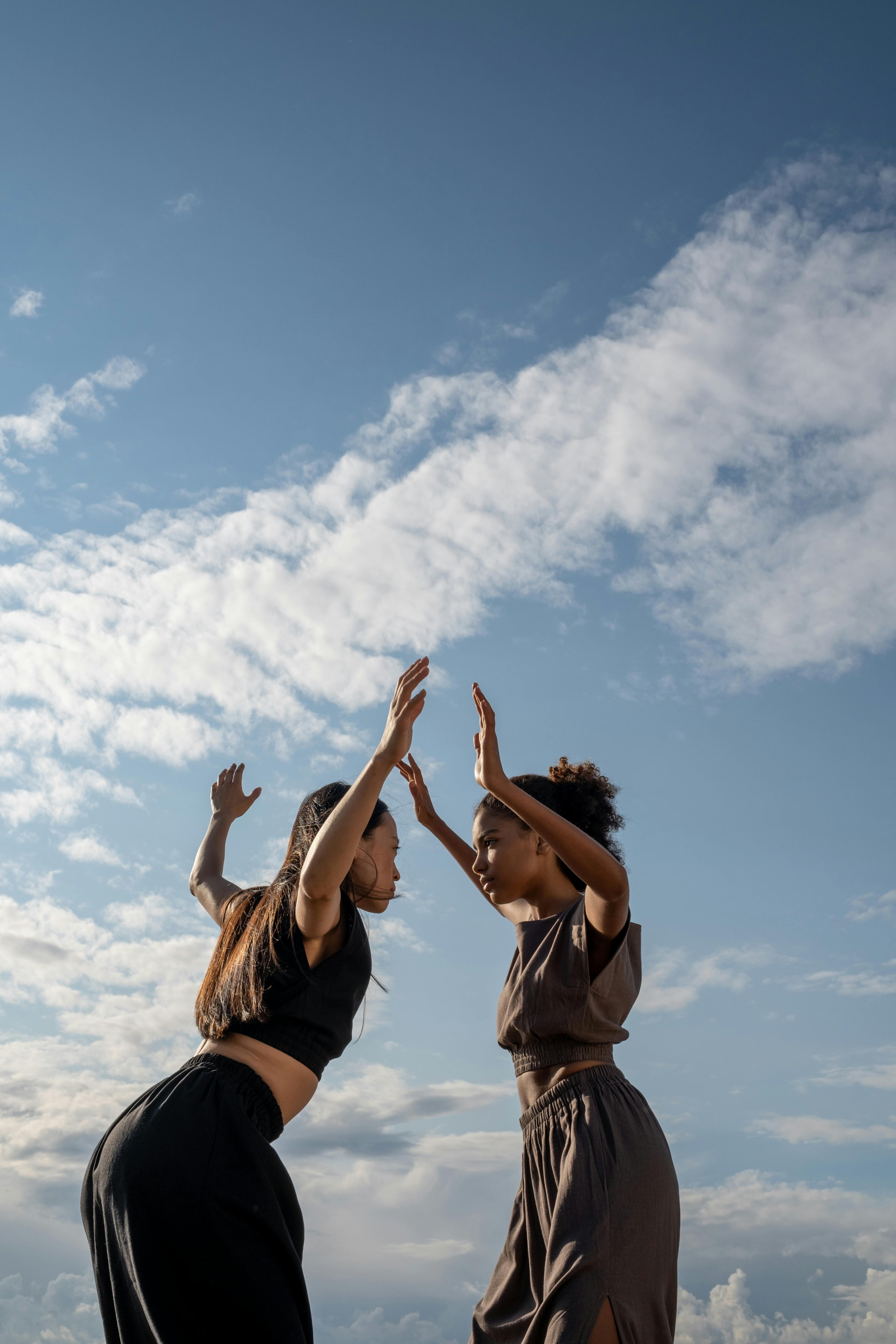 A Low Angle Shot of Women Dancing Face to Face while Raising Arms ...