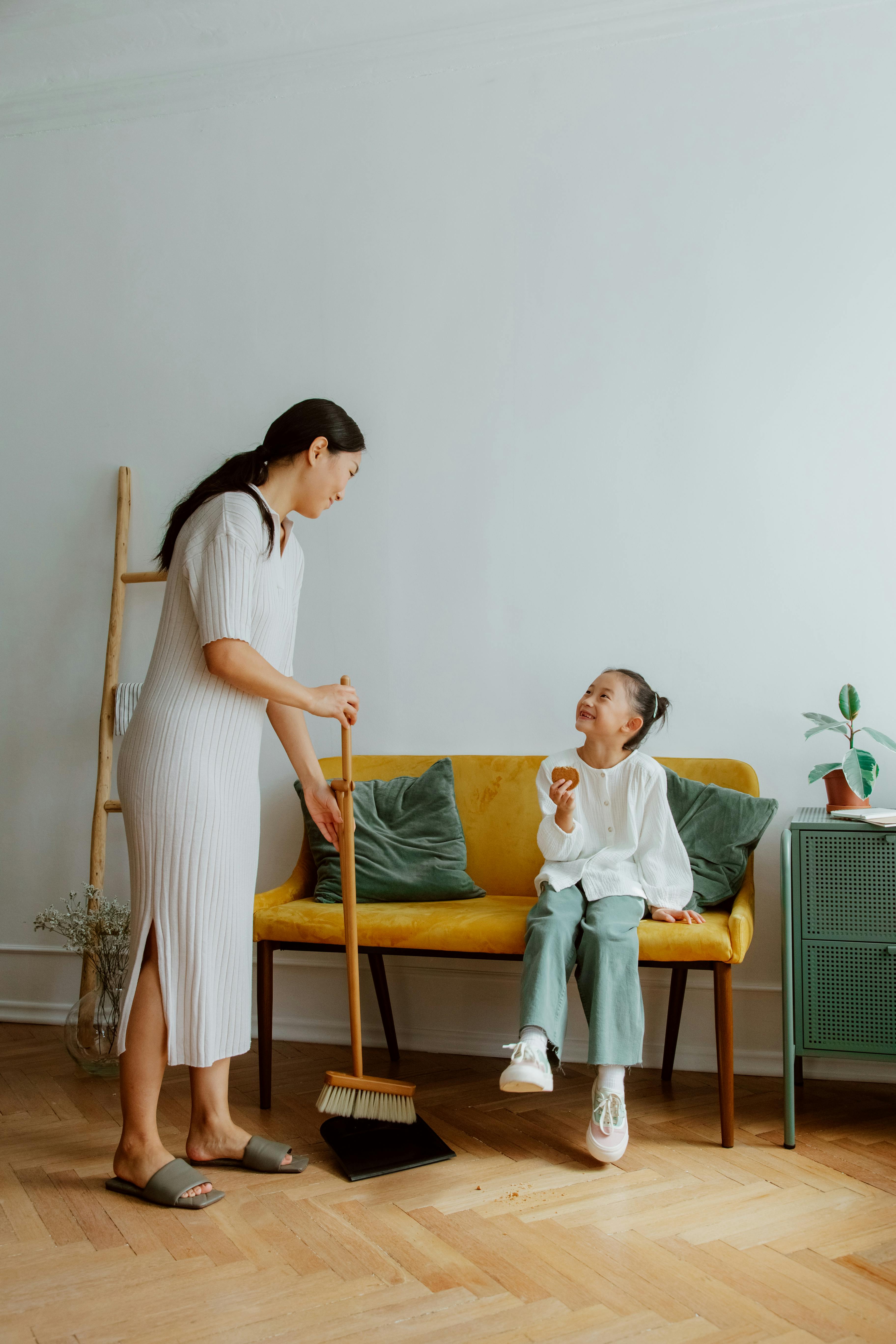 Mother Sweeping and Daughter Eating Cookie · Free Stock Photo
