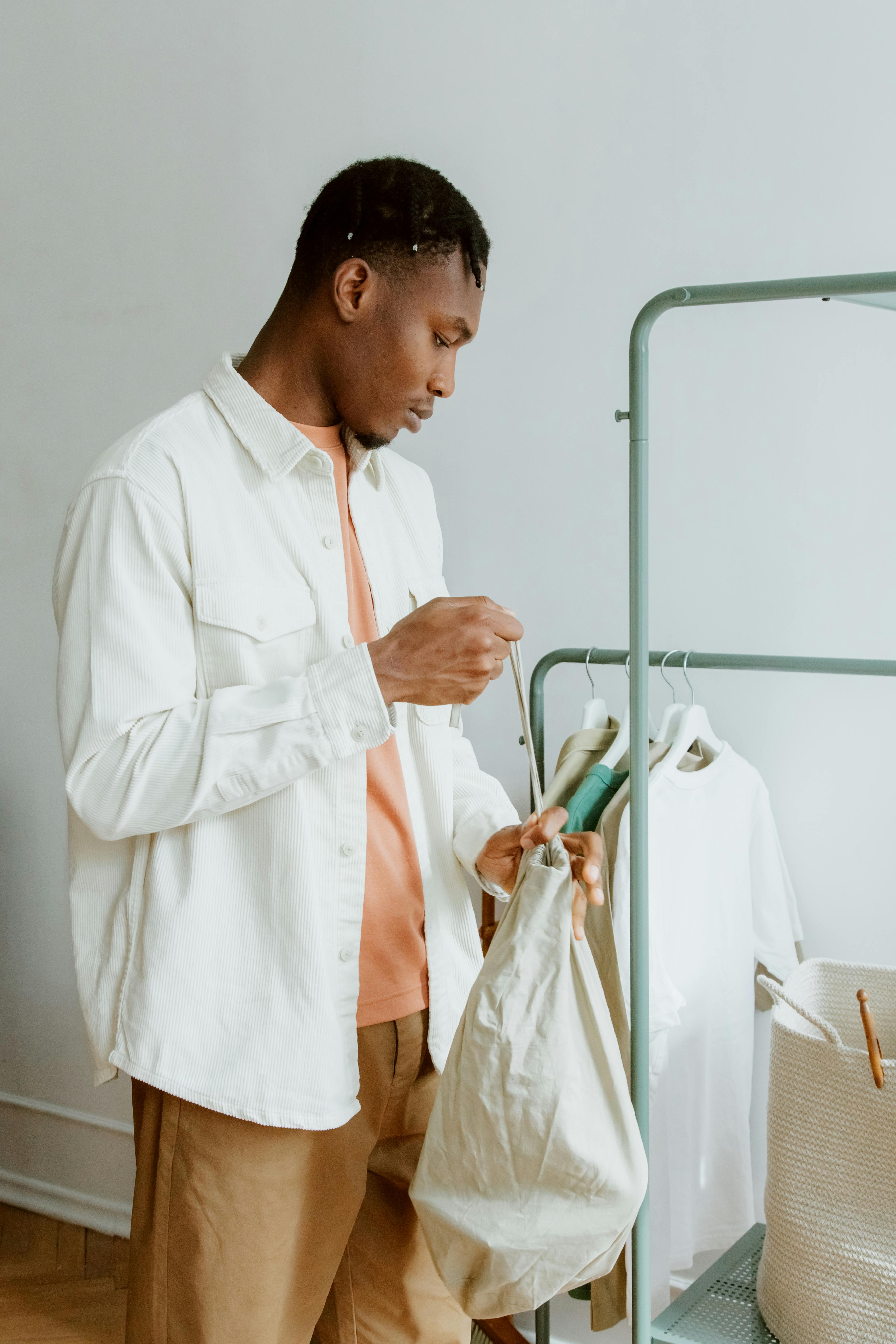 Man with Cloth Bag Standing Next to Clothing Rack · Free Stock Photo