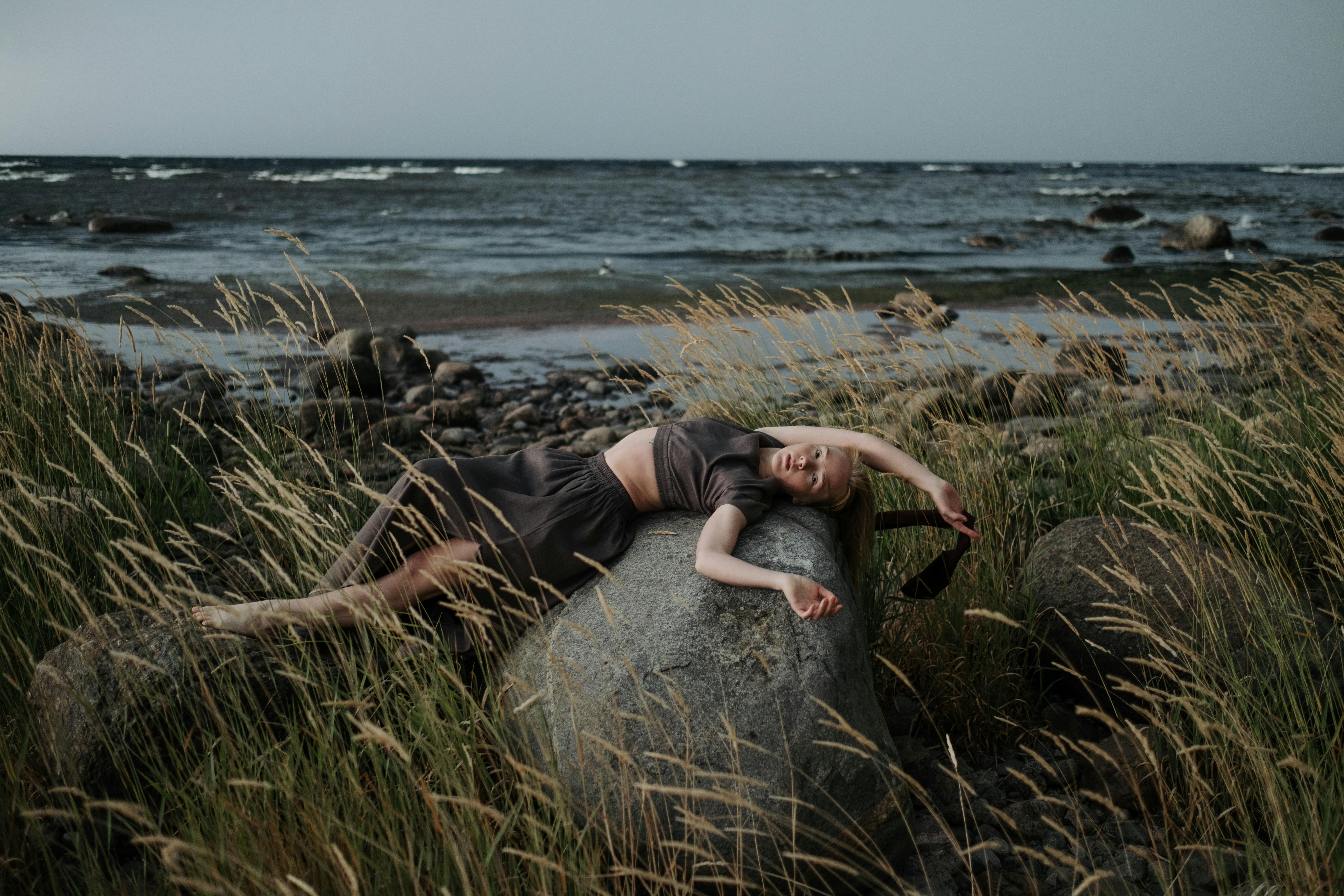 Woman Lying on Rocks on a Shore · Free Stock Photo