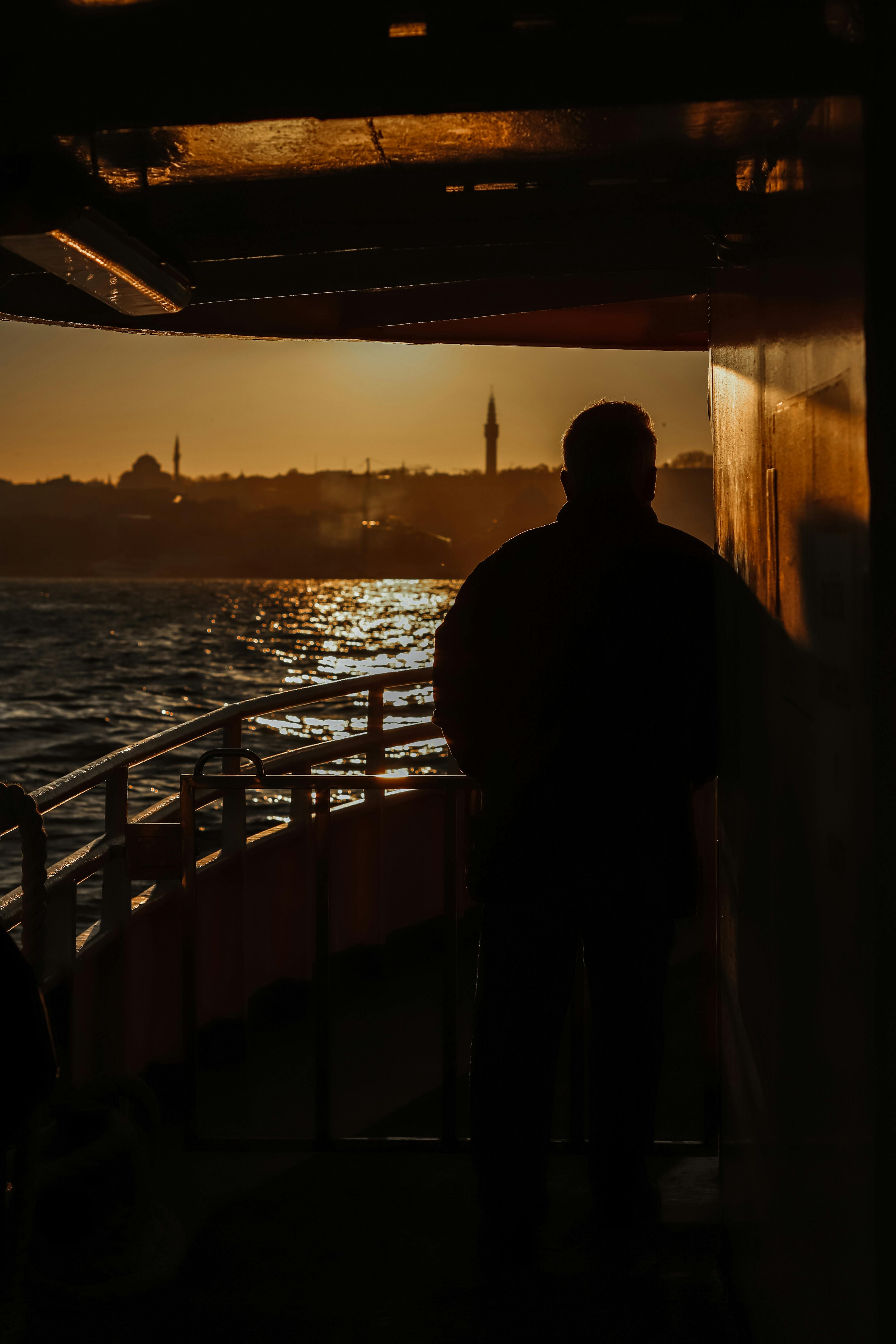 Silhouette of Man Standing on Ship during Sunset · Free Stock Photo