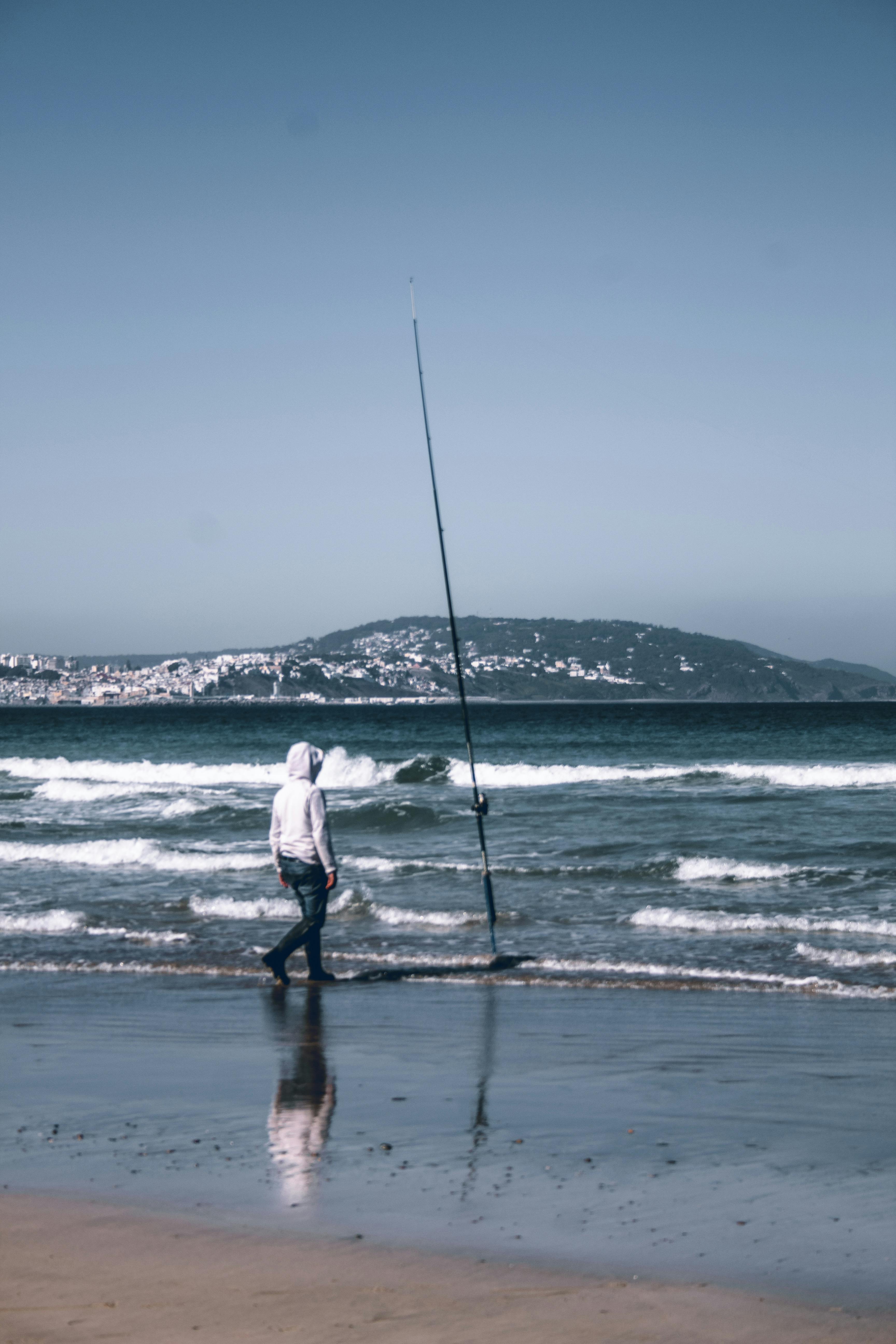 A Fisherman Surf Casting at the Beach · Free Stock Photo