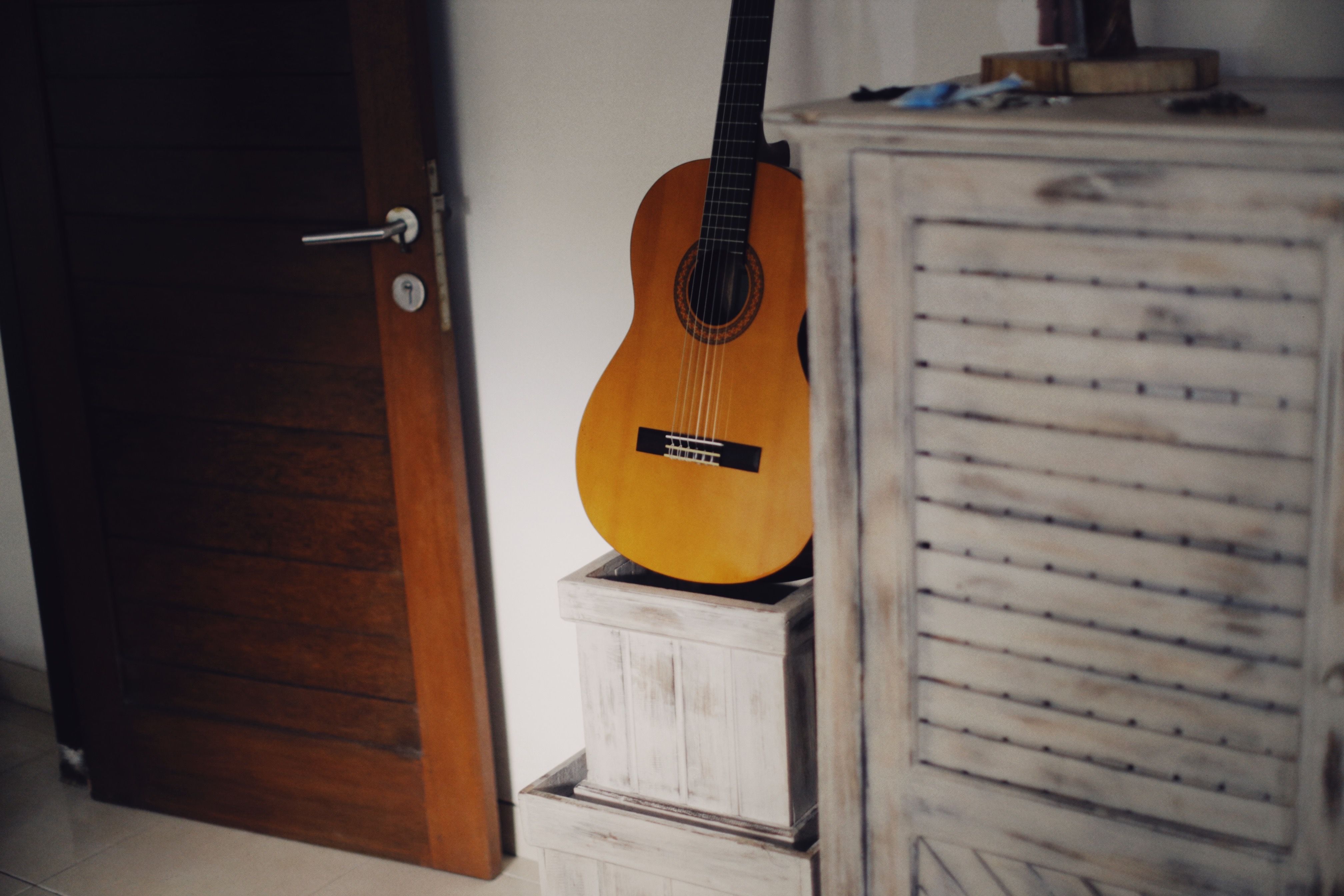 An Acoustic Guitar Leaning on a Wooden Furniture · Free Stock Photo