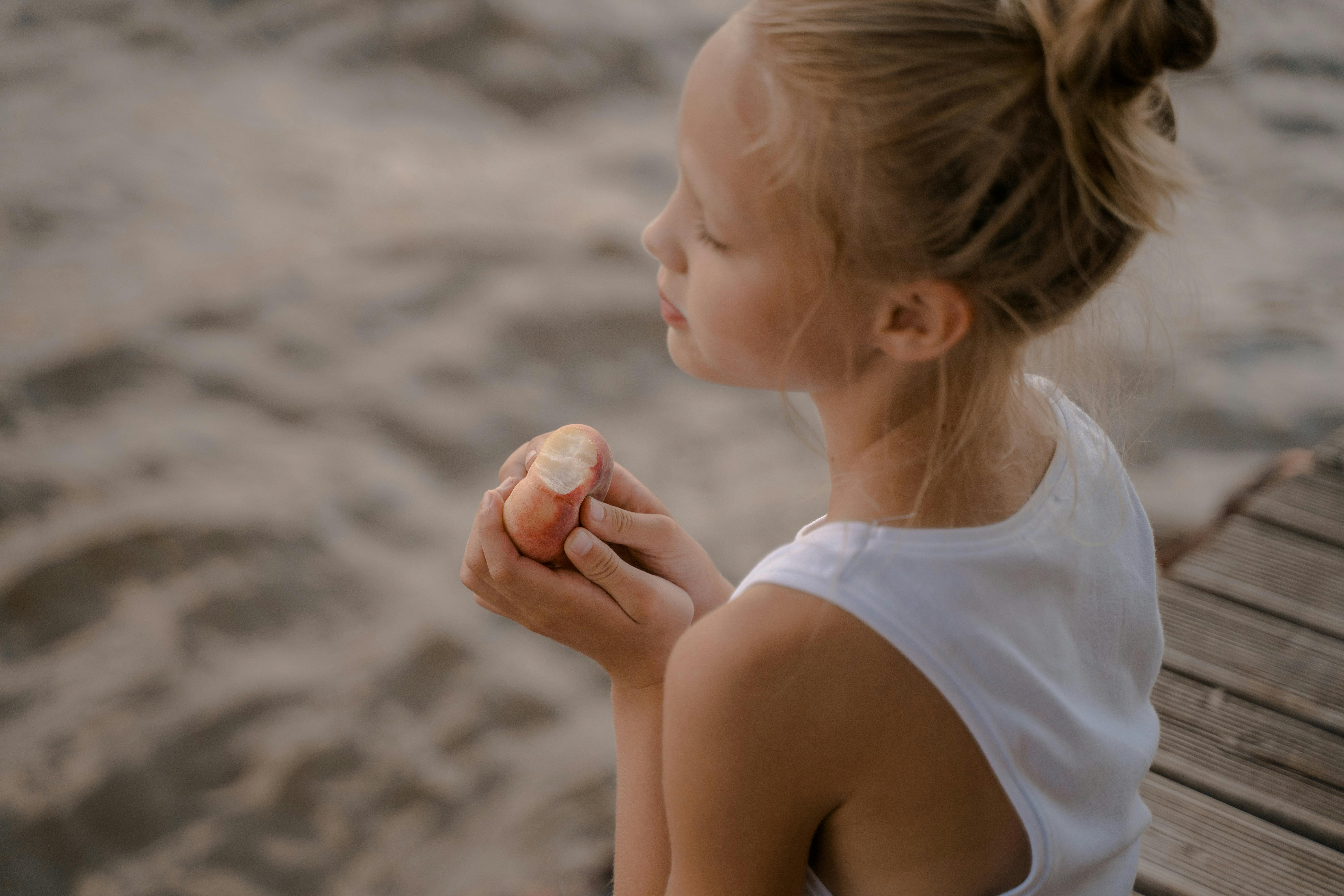 Girl Eating a Peach on a Pier · Free Stock Photo