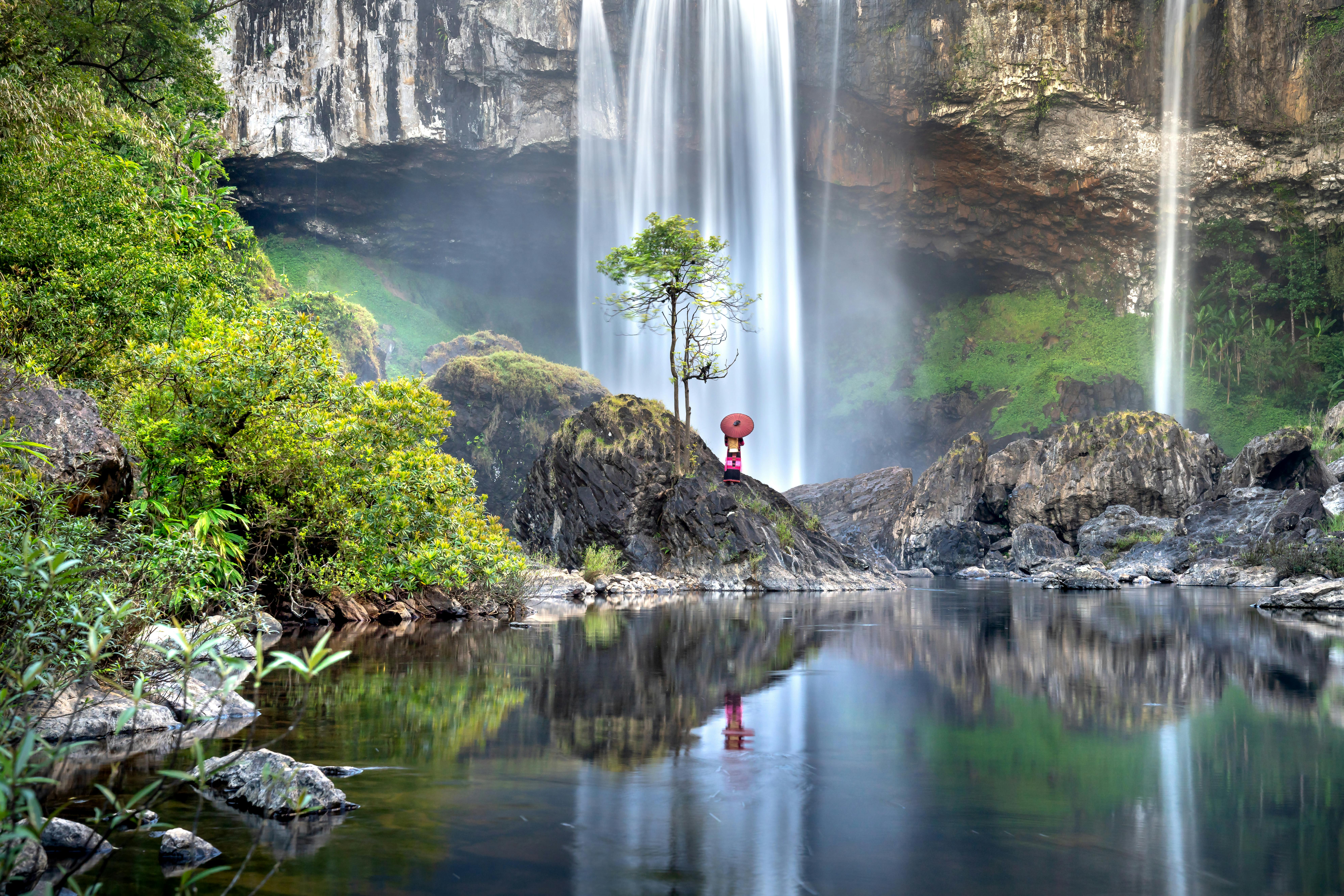 A Person Standing on a Rock Near Waterfalls · Free Stock Photo