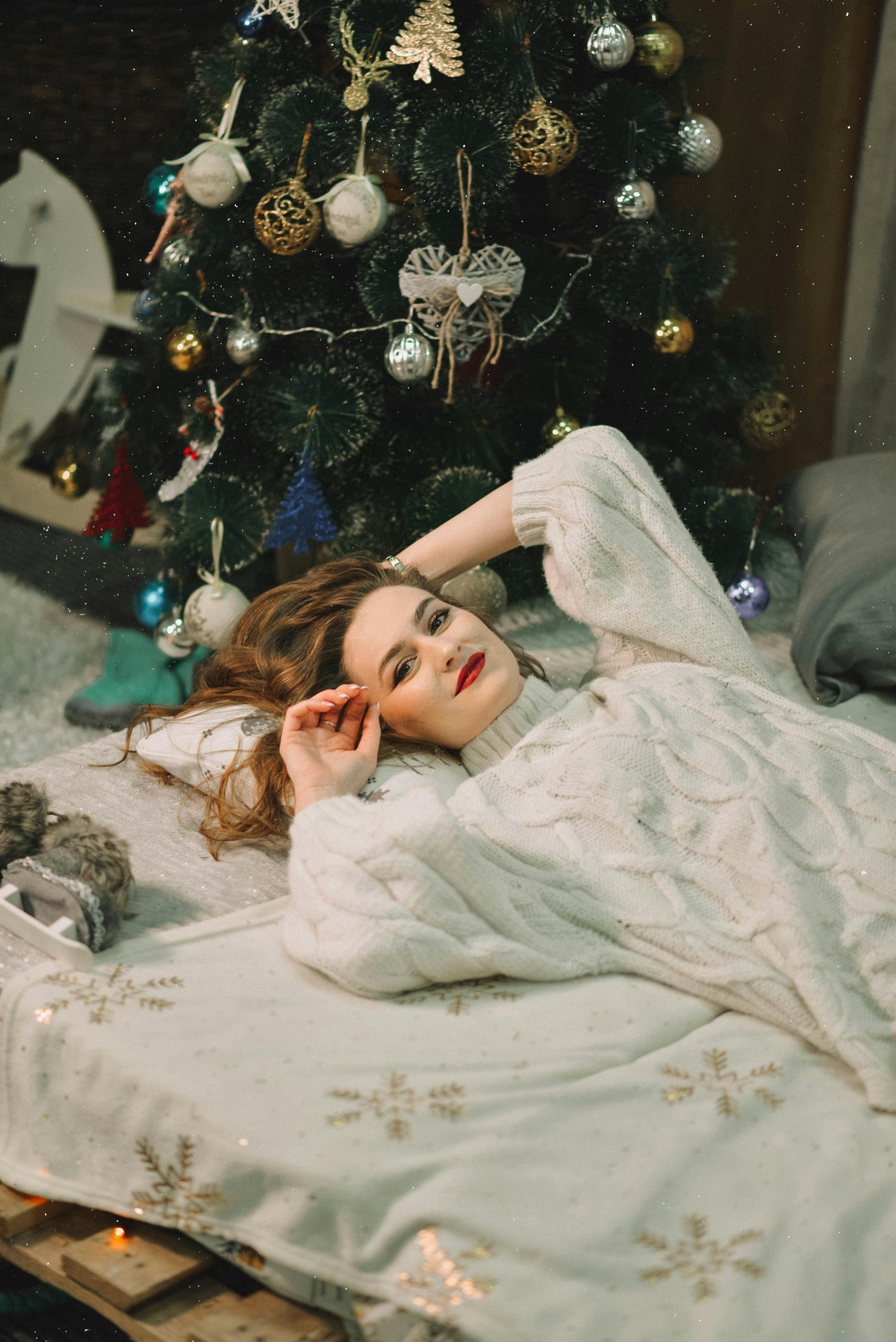 Woman in a Sweater Lying on a Bed by a Christmas Tree · Free Stock Photo