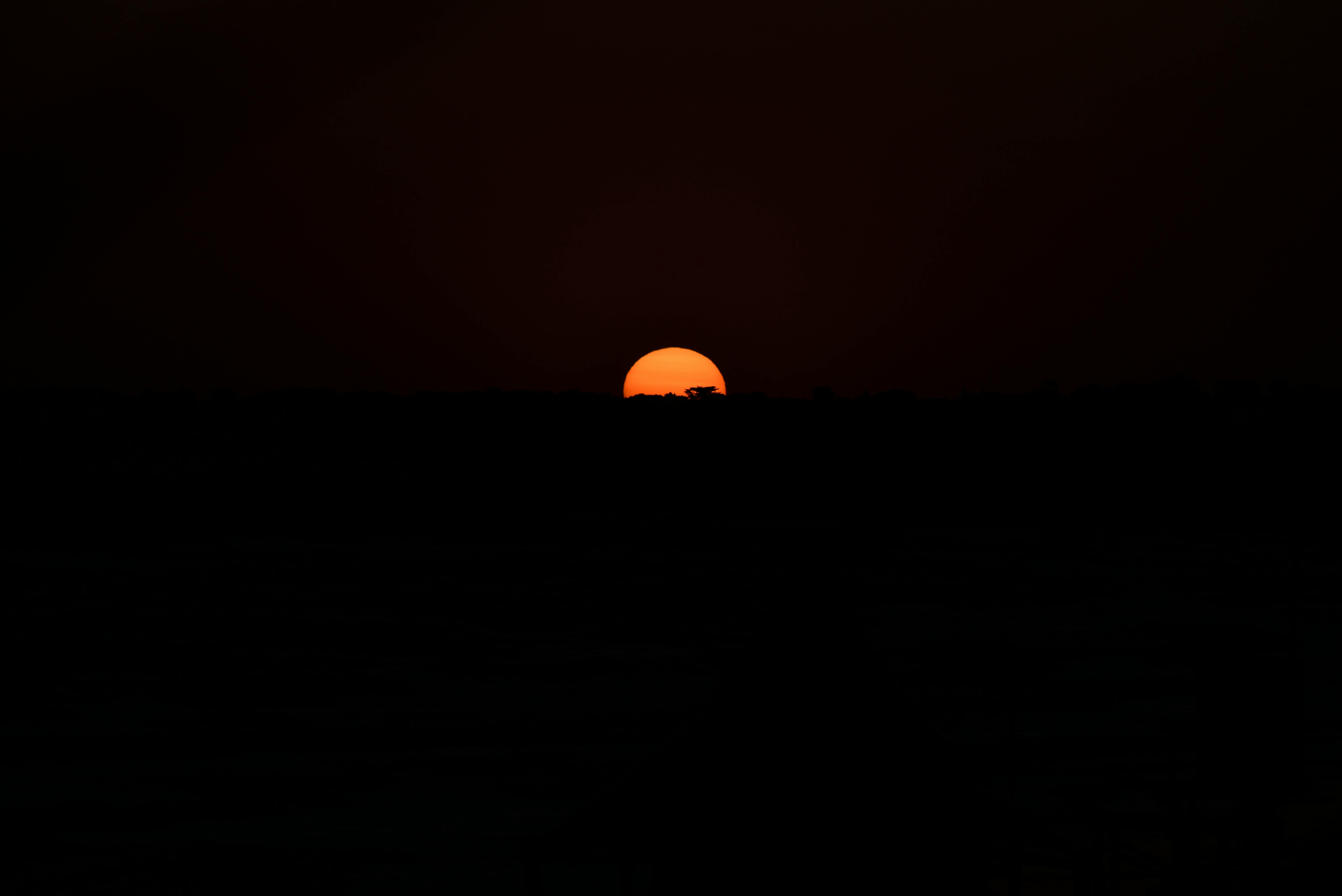 Orange Sun Setting in Dark Landscape · Free Stock Photo