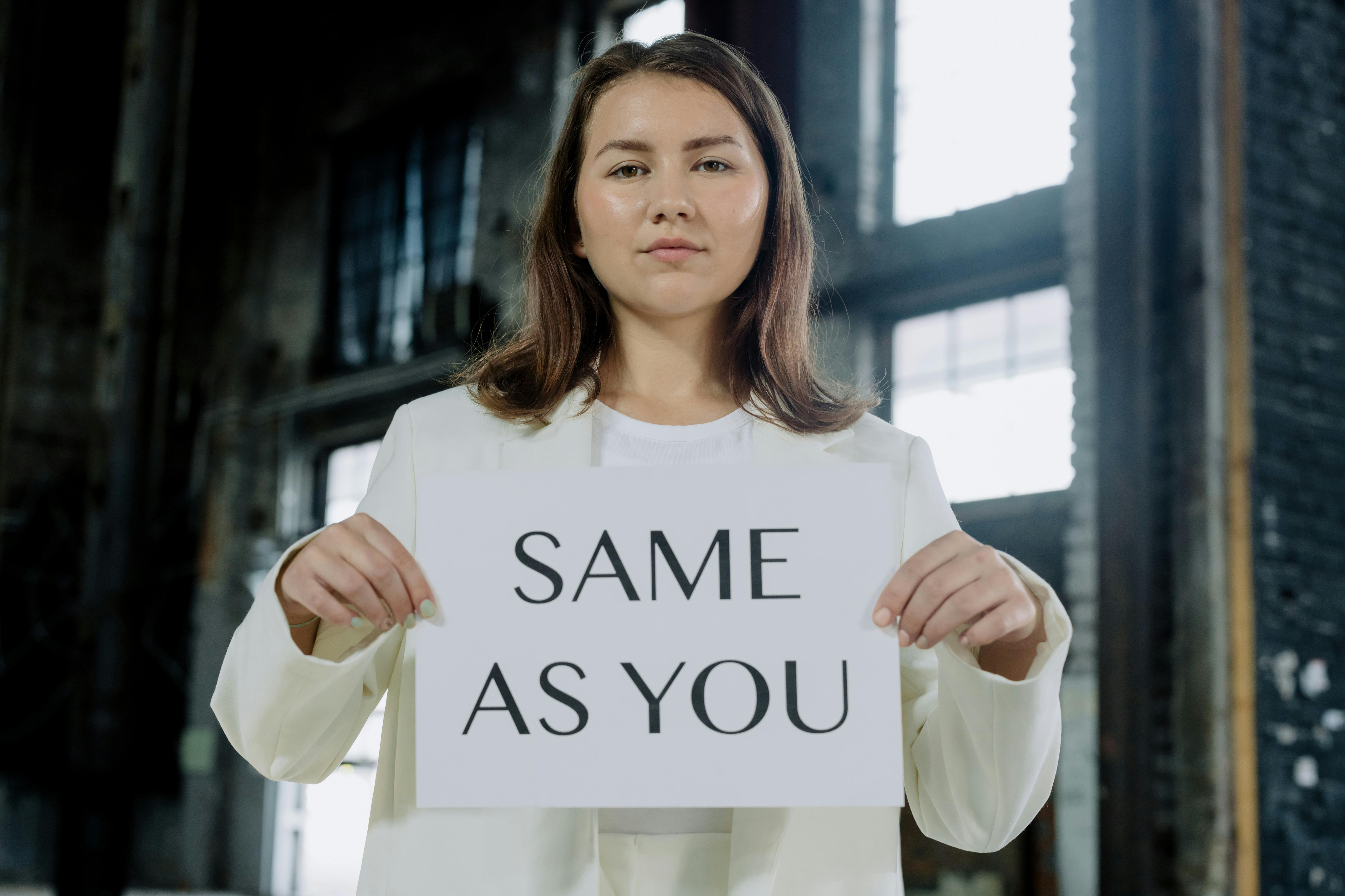 A Group of People in White Clothes Holding a Paperboard with a Text ...