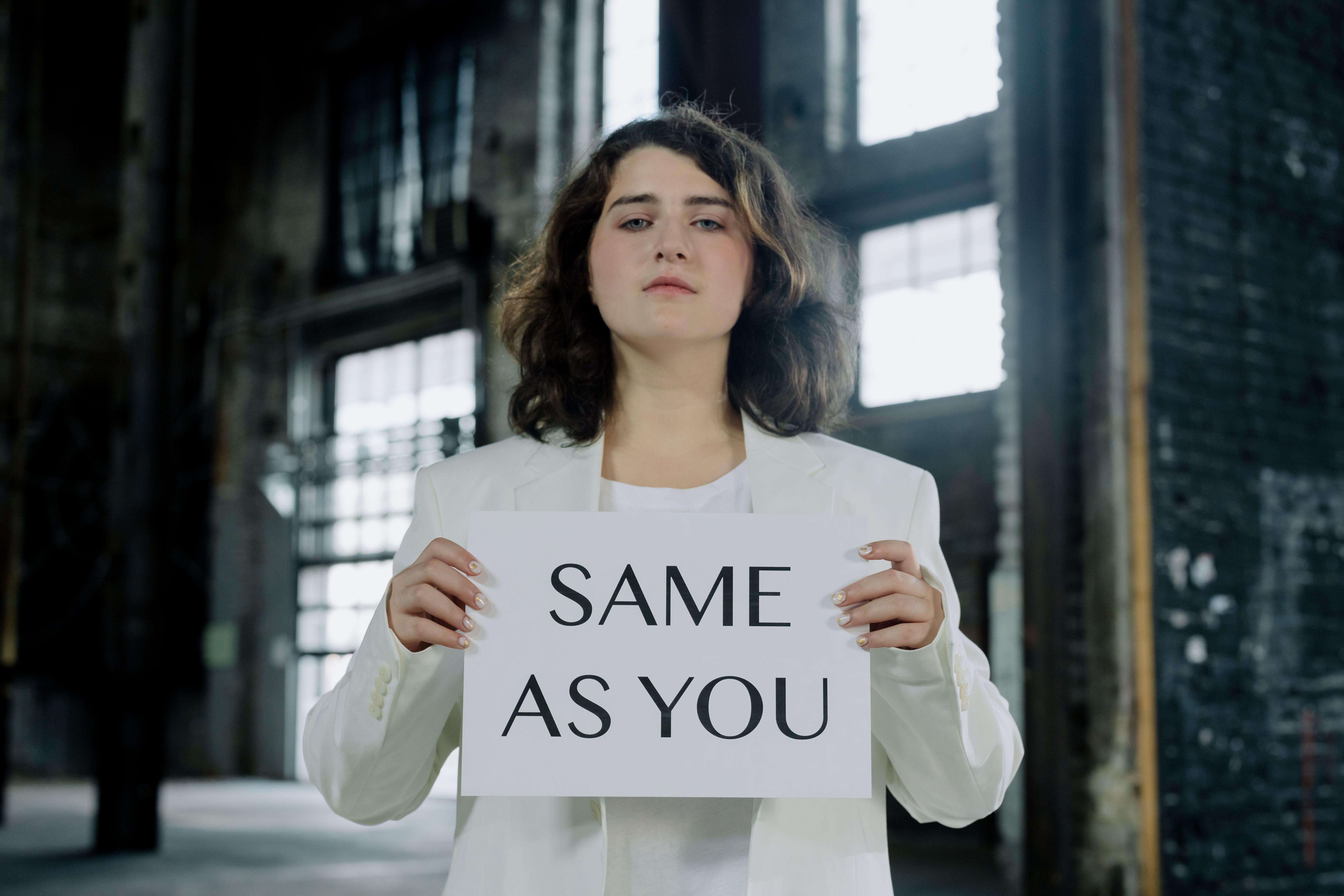 A Woman in White Blazer Holding White Paperboard with a Text Same As ...