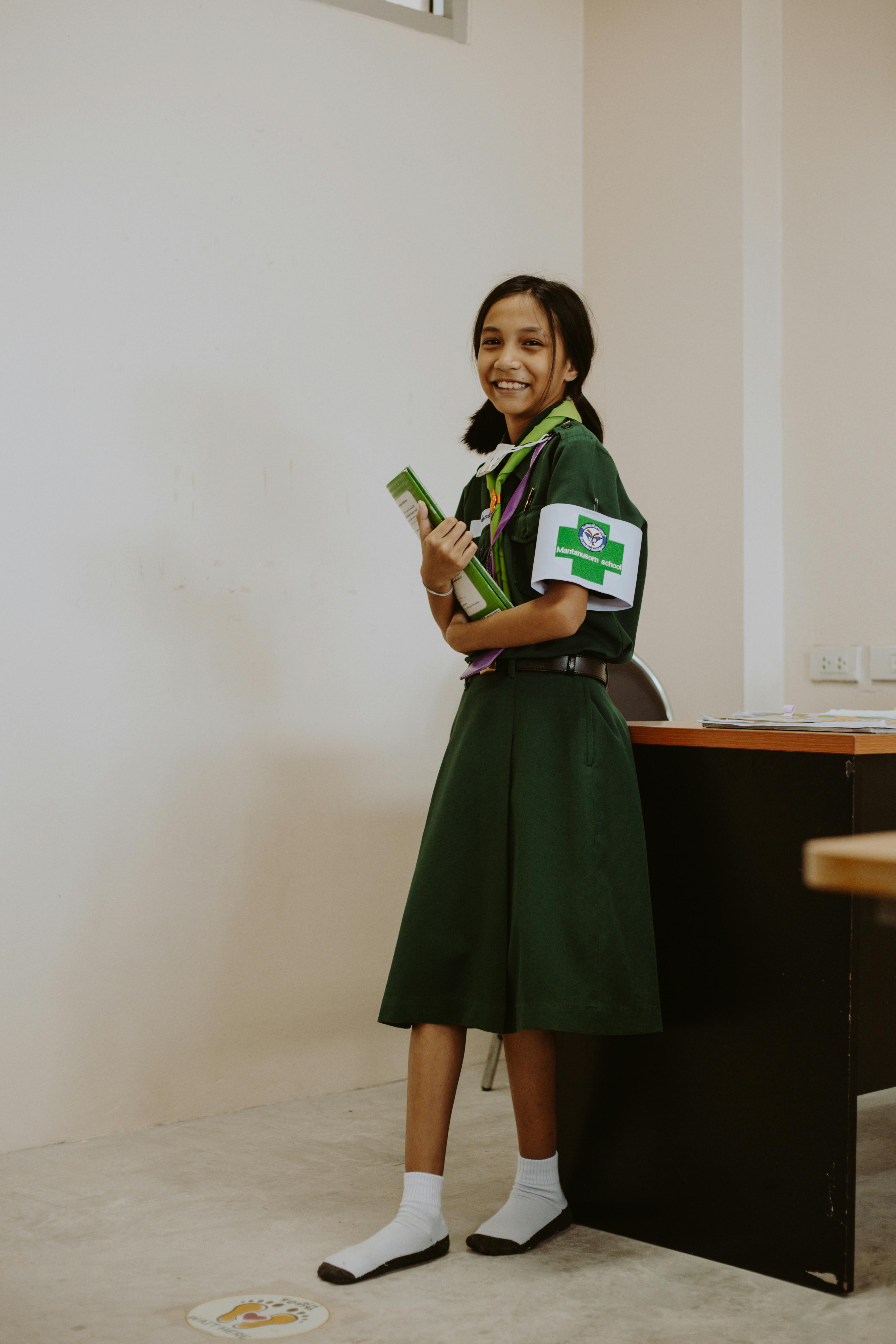 Portrait of Smiling Scout Girl Sitting in Classroom · Free Stock Photo