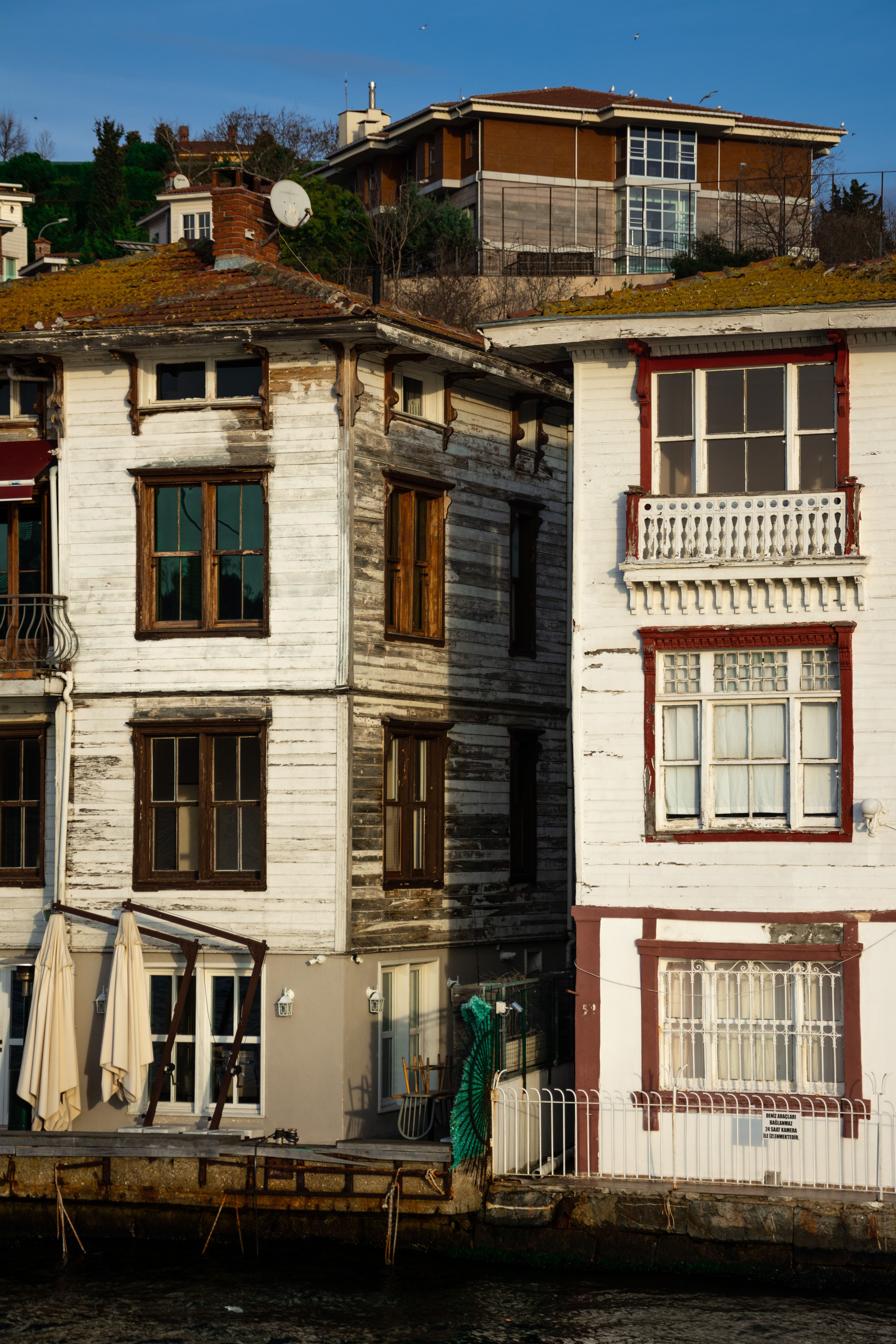 A White Wooden Shabby House Beside a White and Red Concrete Building ...
