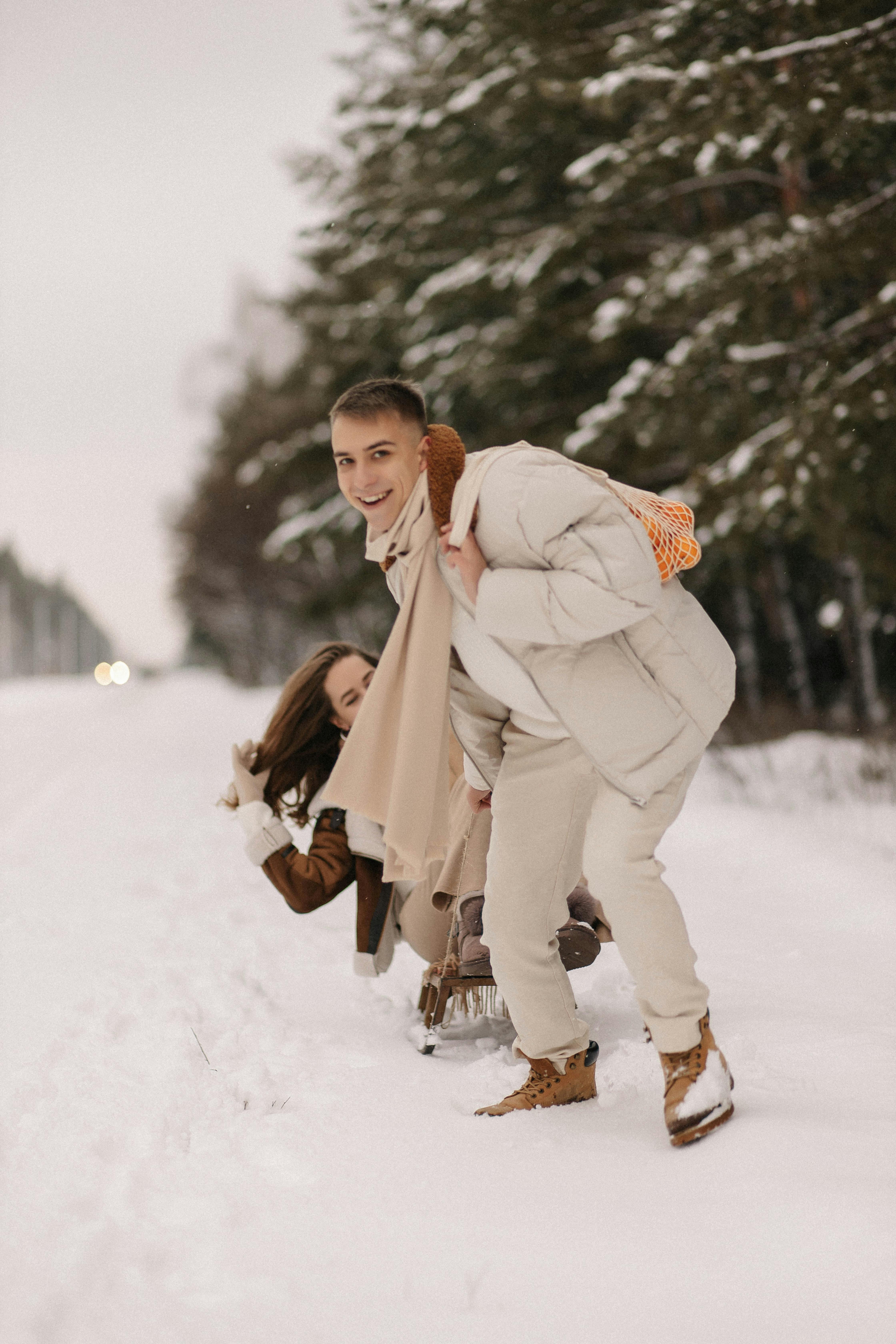 Man Pulling Woman on Sled · Free Stock Photo
