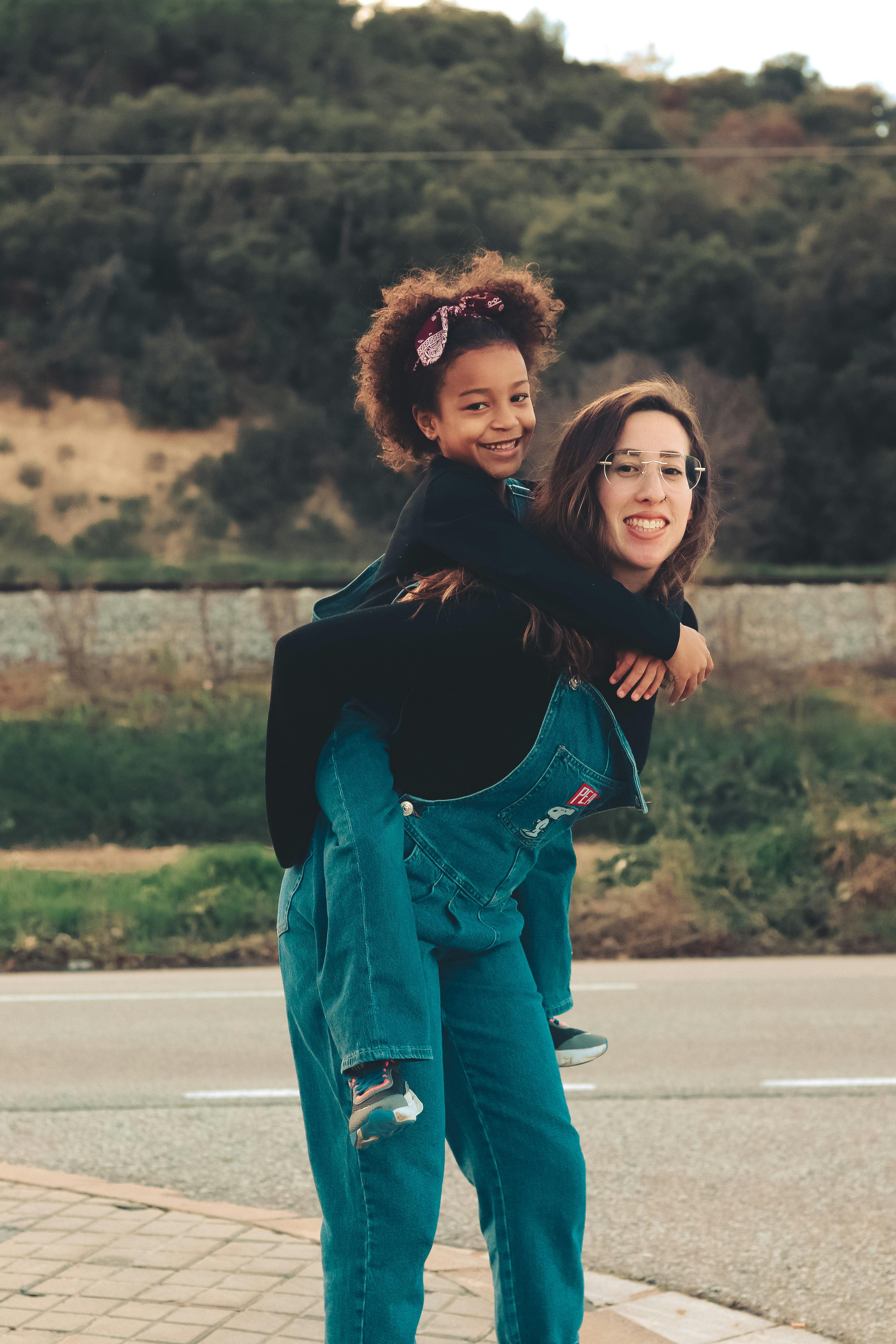 A Girl Riding on Her Mother's Back · Free Stock Photo