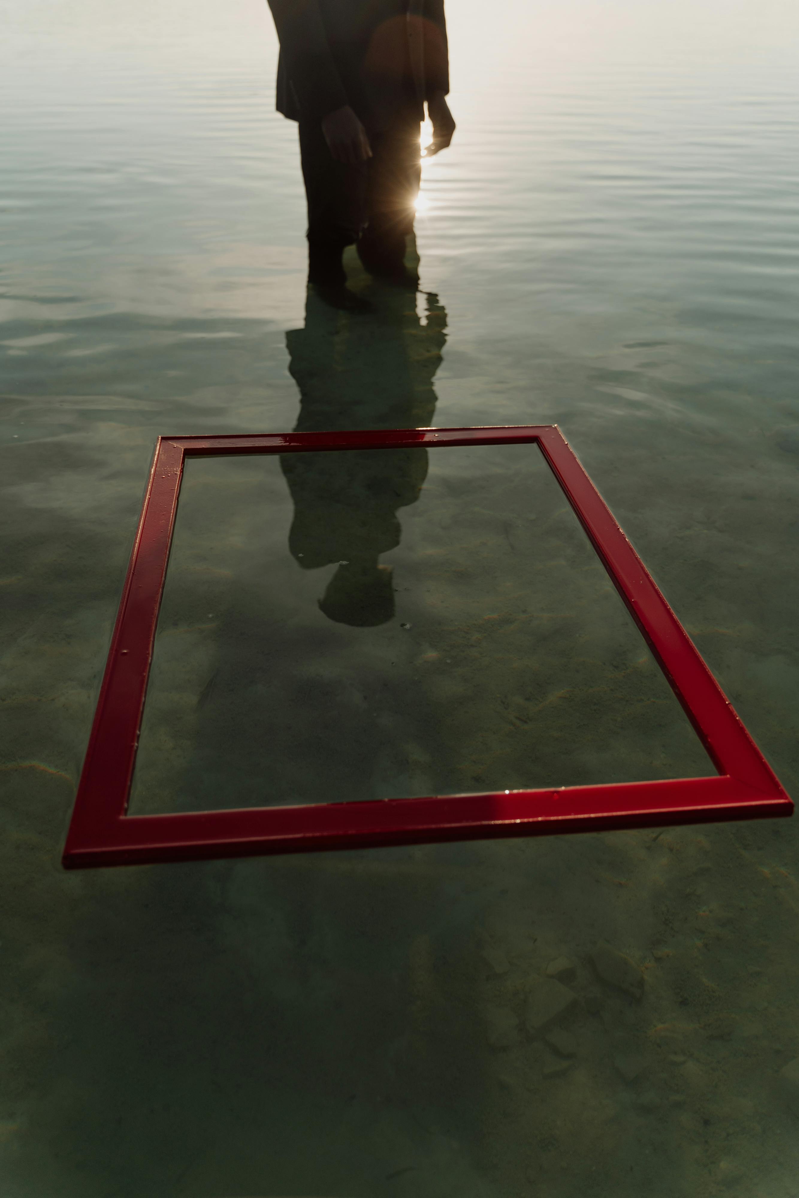 Man Standing in Lake, Frame Floating on Surface · Free Stock Photo