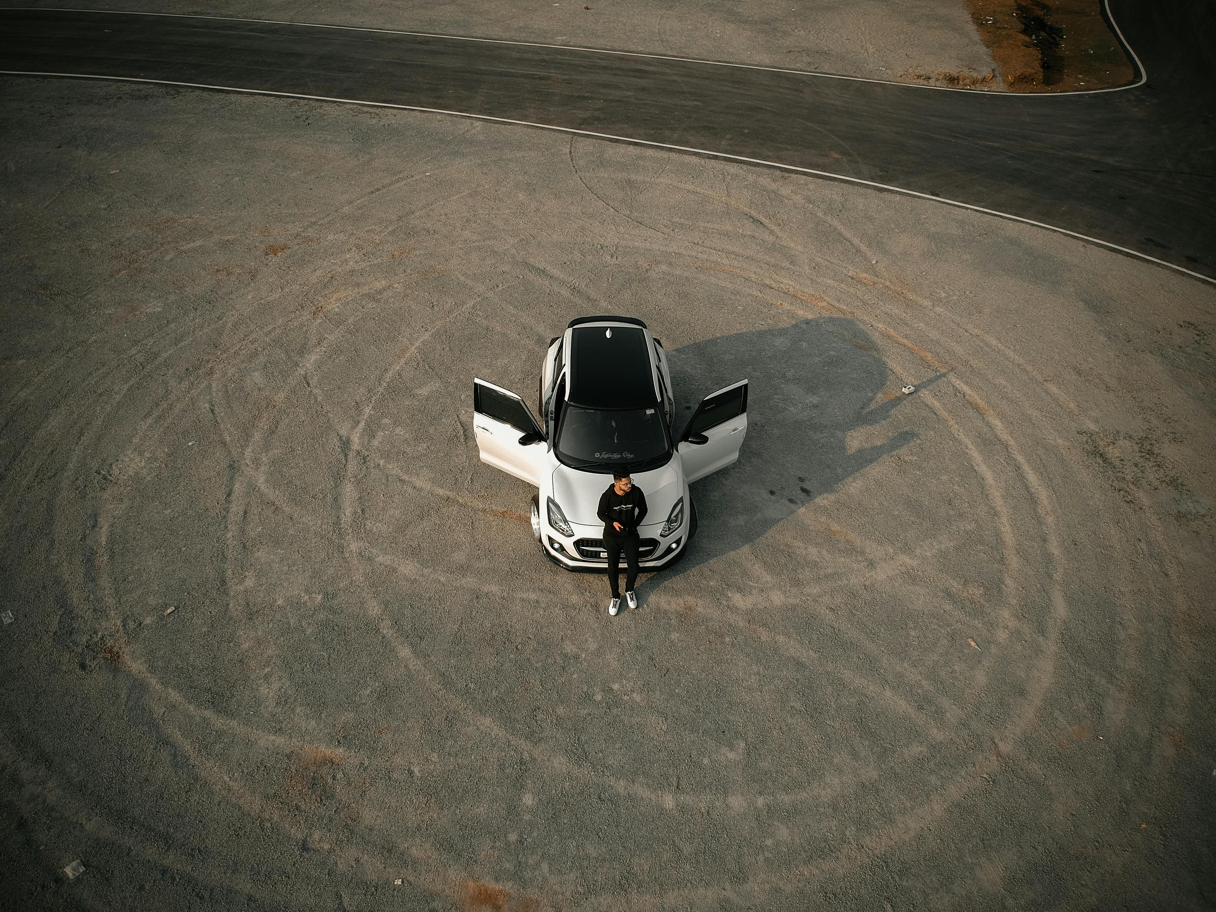 Man Sitting on Car Hood in Aerial Photography · Free Stock Photo