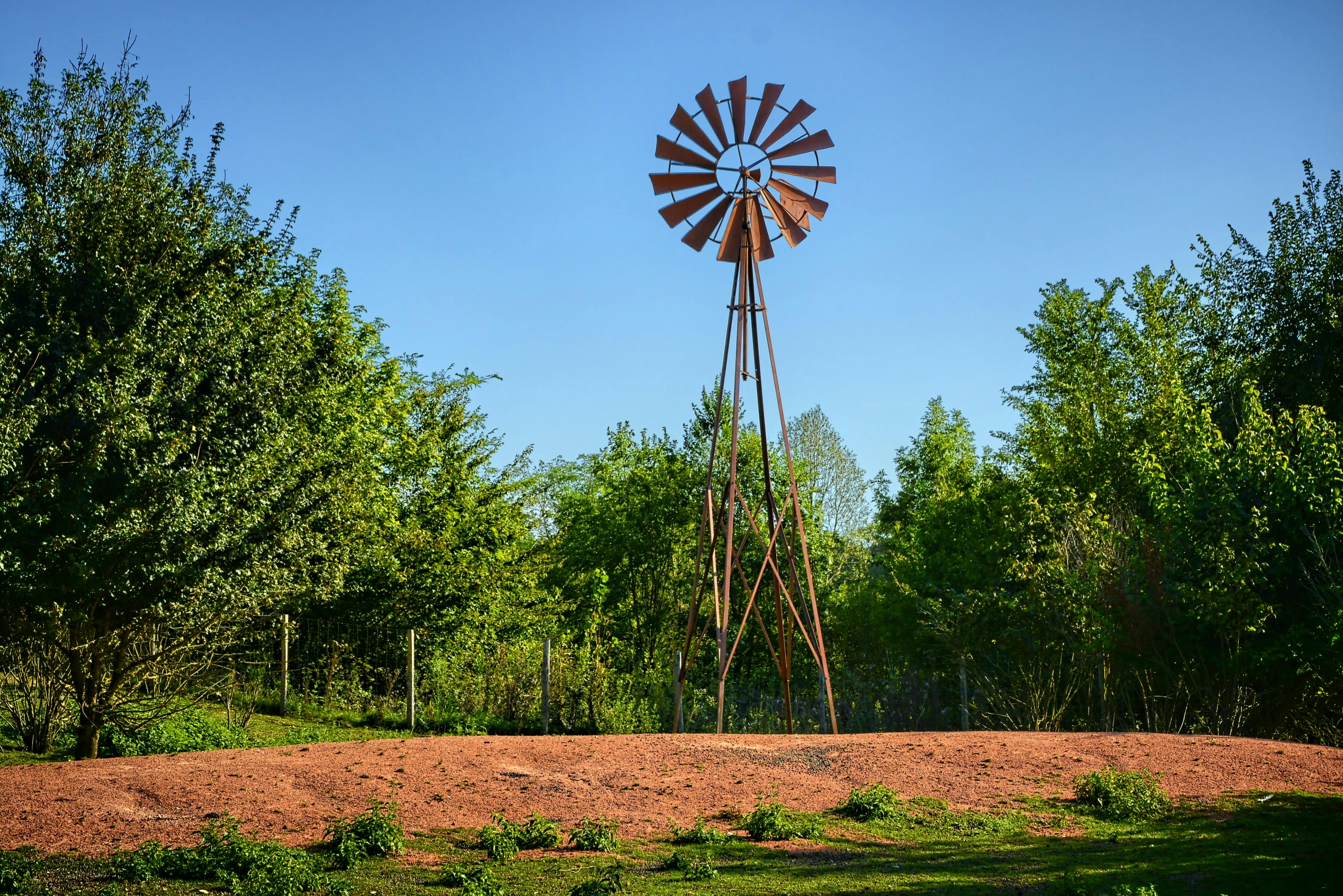 Brown Windmill Near Green Trees Under Blue Sky · Free Stock Photo