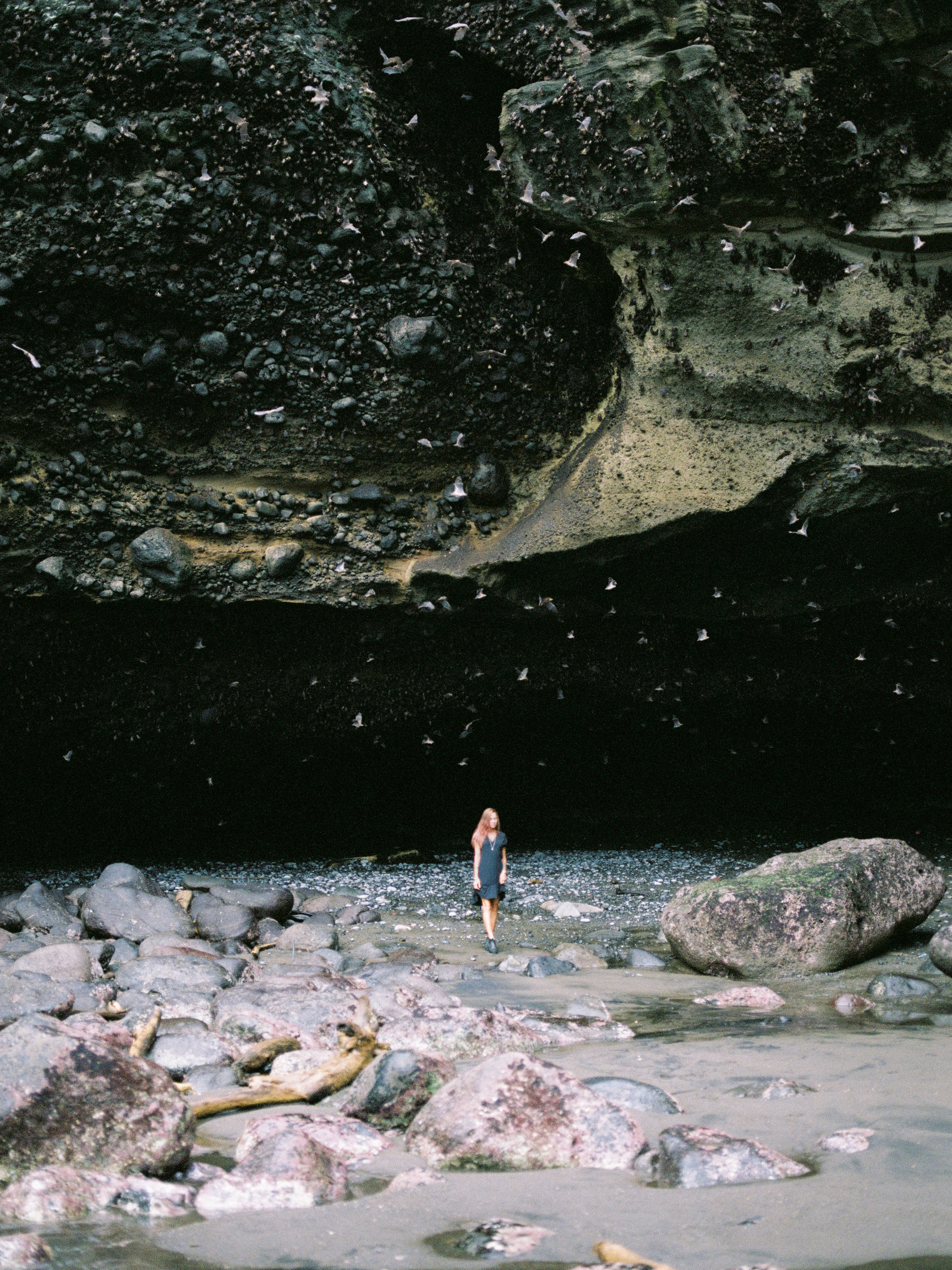 Woman Walking near Cave under Rocks on Sea Shore · Free Stock Photo