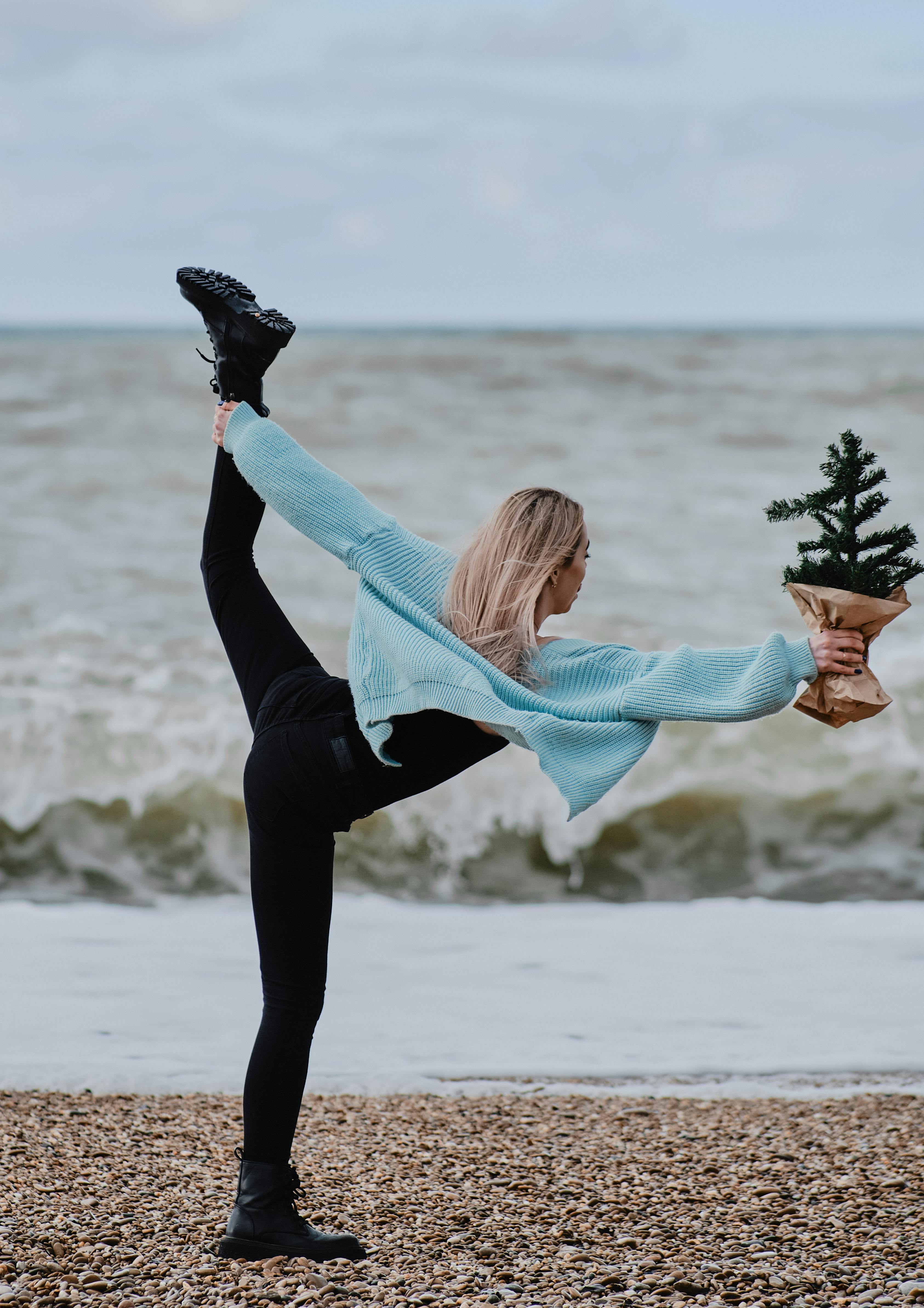 Person Raising Hands and Jumping on Seashore Holding Pine Tree Branch ...