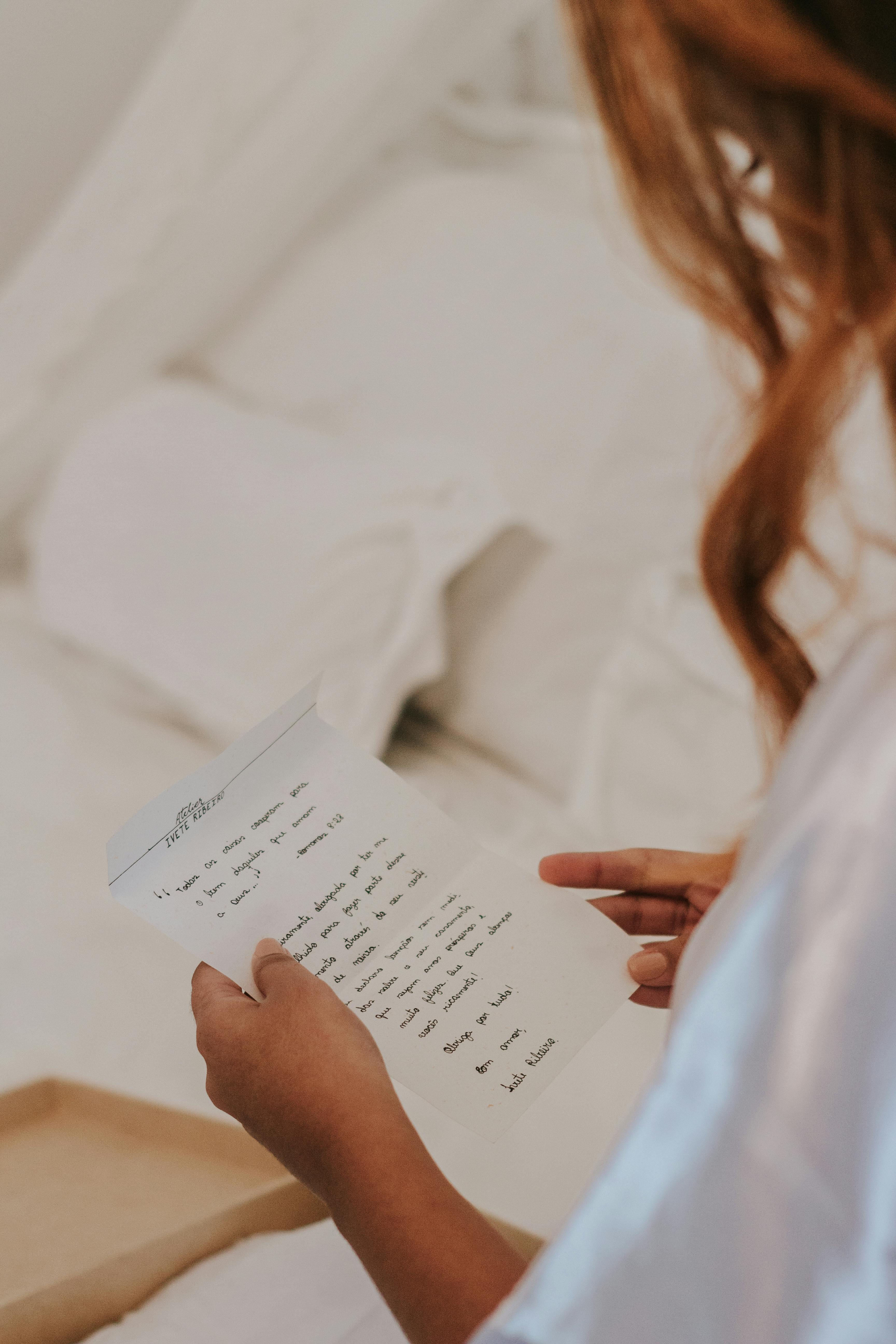 Person in White Shirt Holding and Reading a Letter · Free Stock Photo