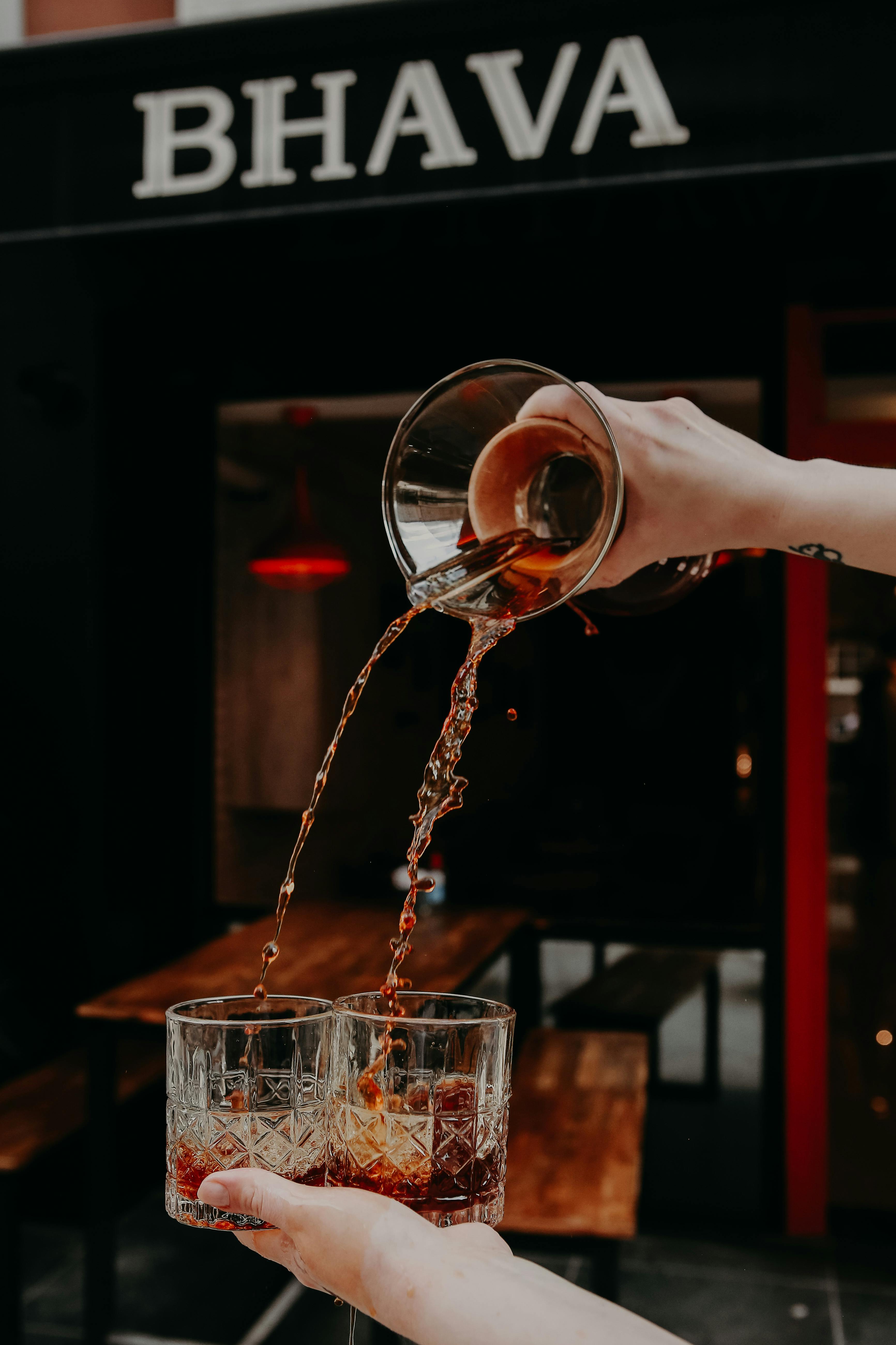 Person Pouring Drink into Glasses · Free Stock Photo