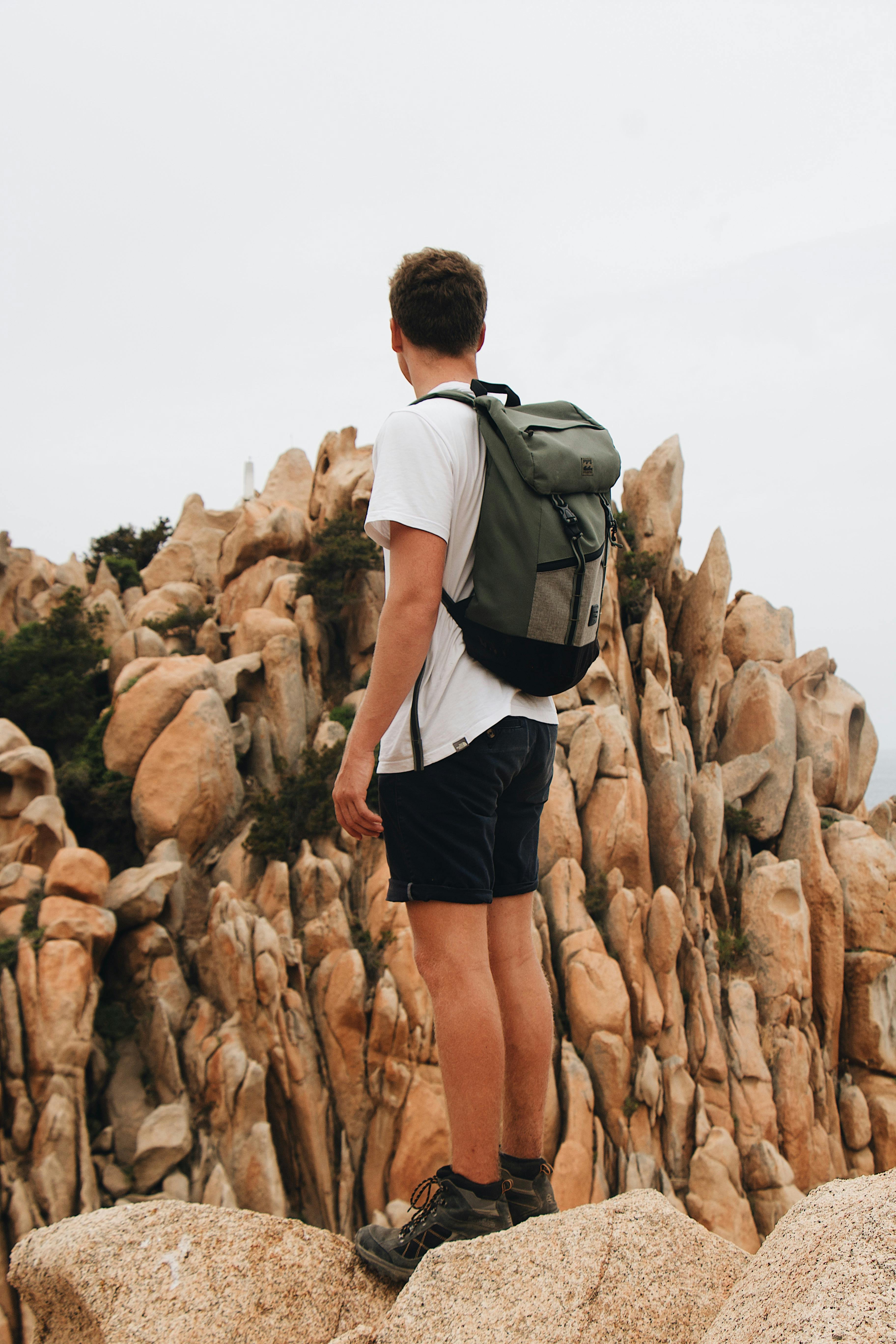 Man Standing on a Rock Looking at a Brown Rock Formation · Free Stock Photo