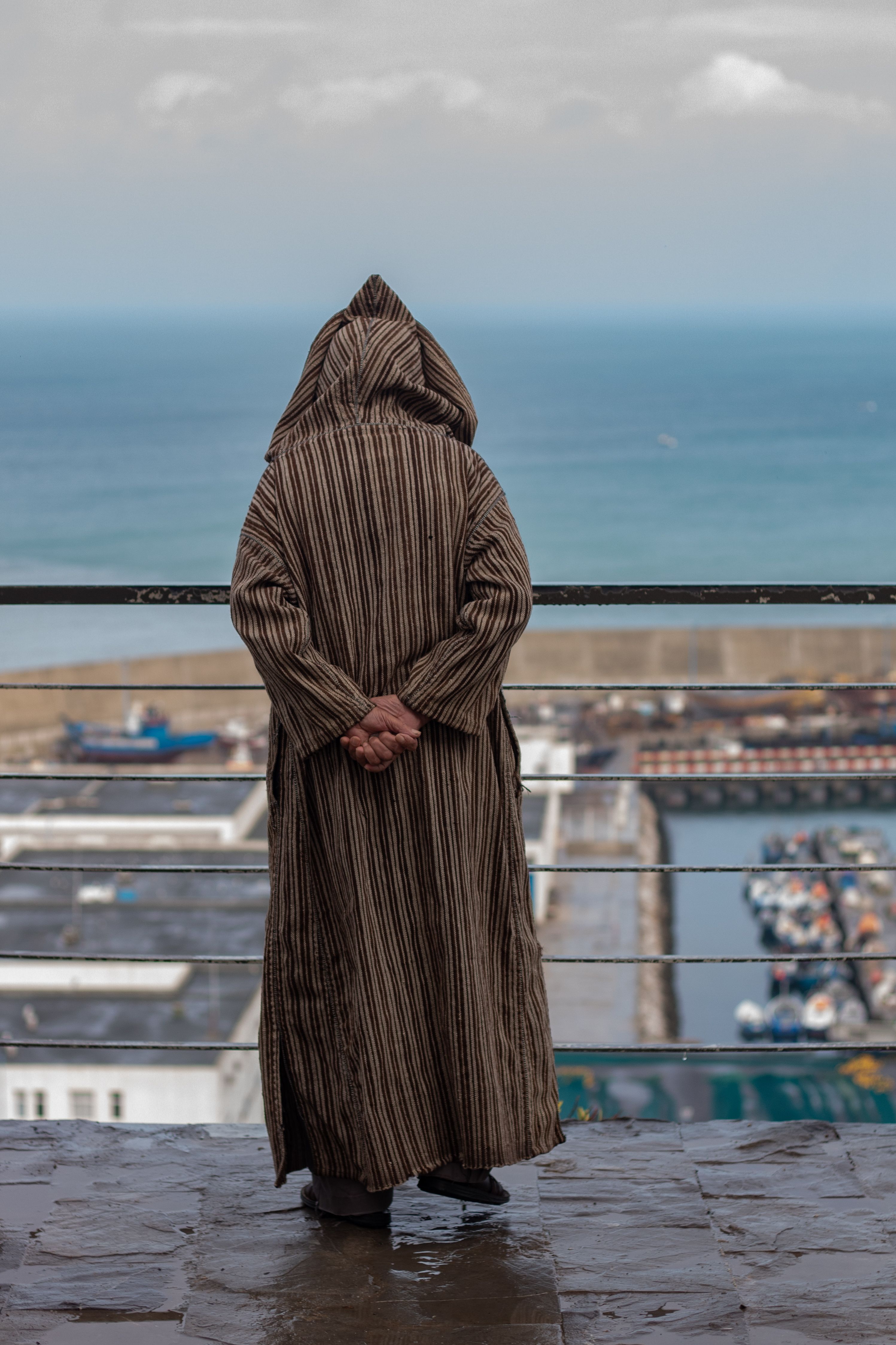 A Person in Brown Robe Standing near the Port · Free Stock Photo