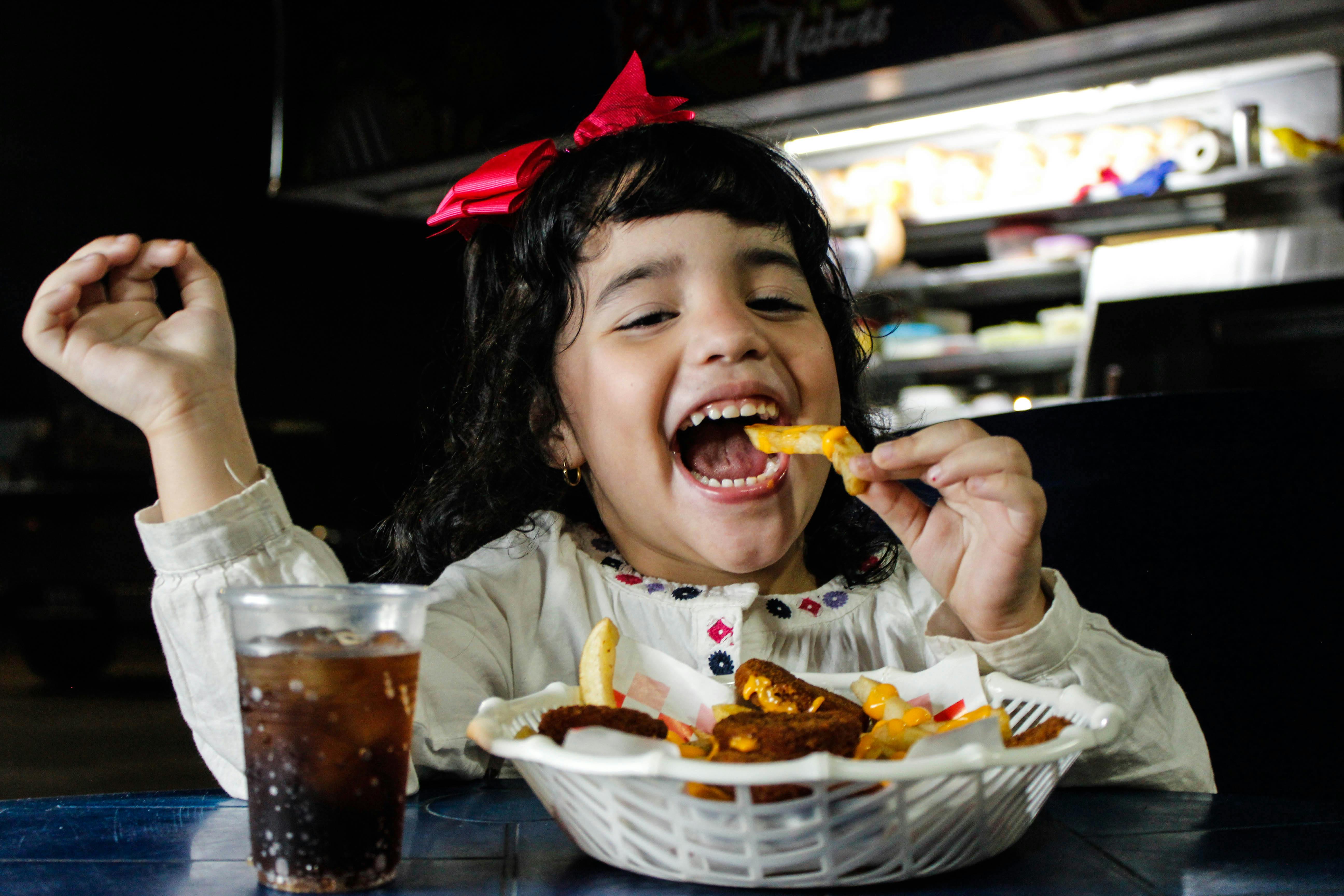 Photo of a Girl Eating Fries · Free Stock Photo