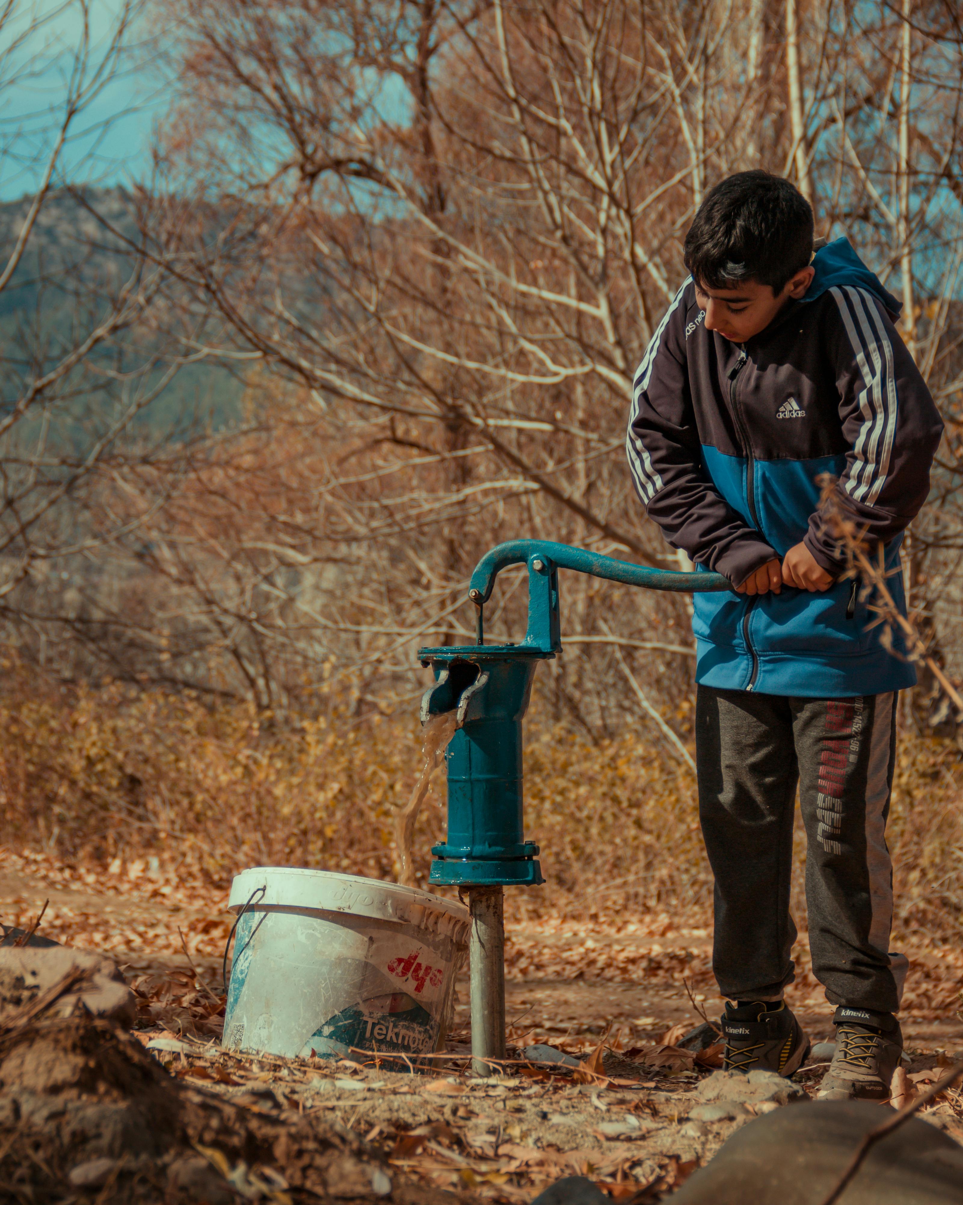 Young Boy Using a Hand Water Pump · Free Stock Photo