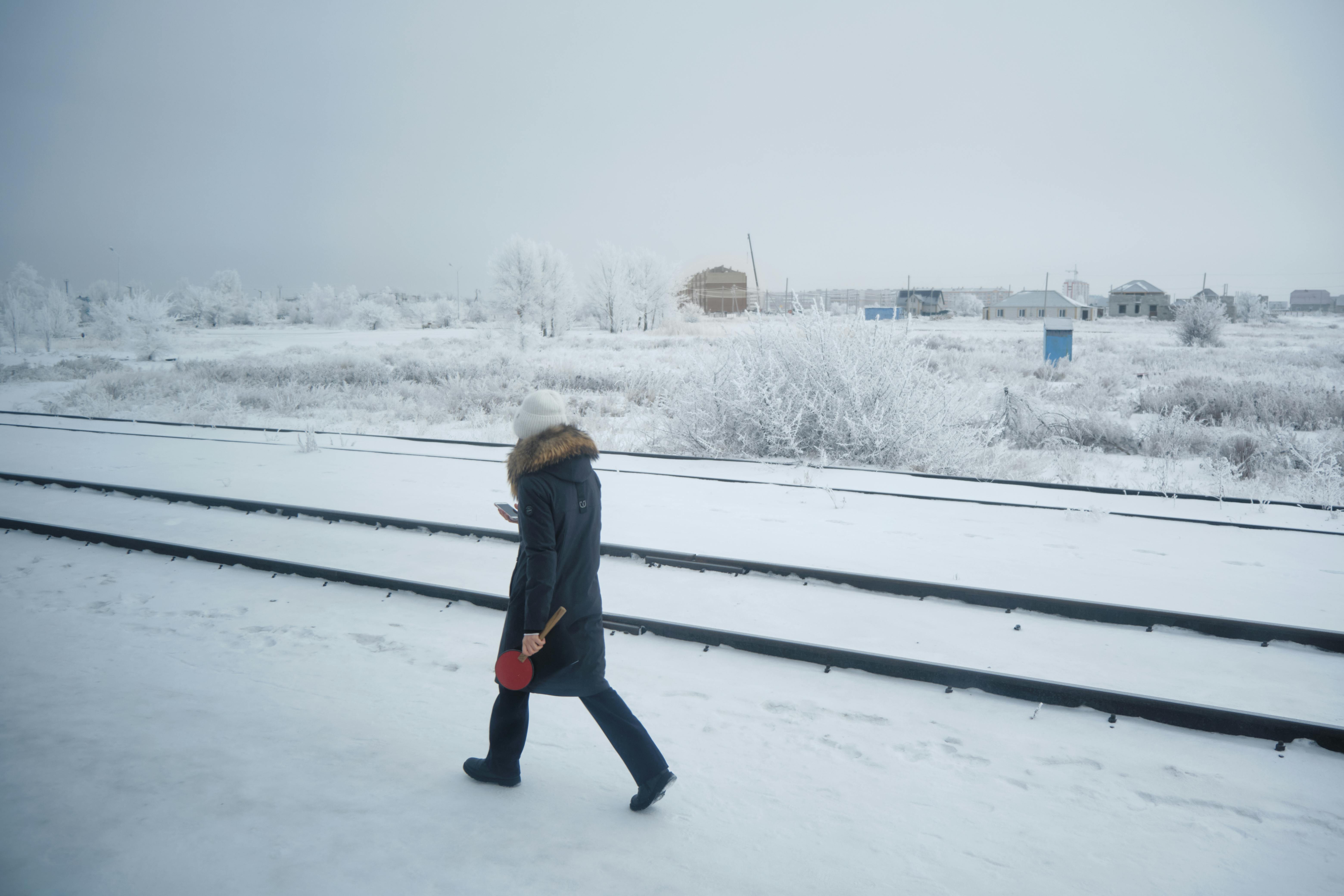 Person in Black Coat Walking on Snow Covered Pathway · Free Stock Photo
