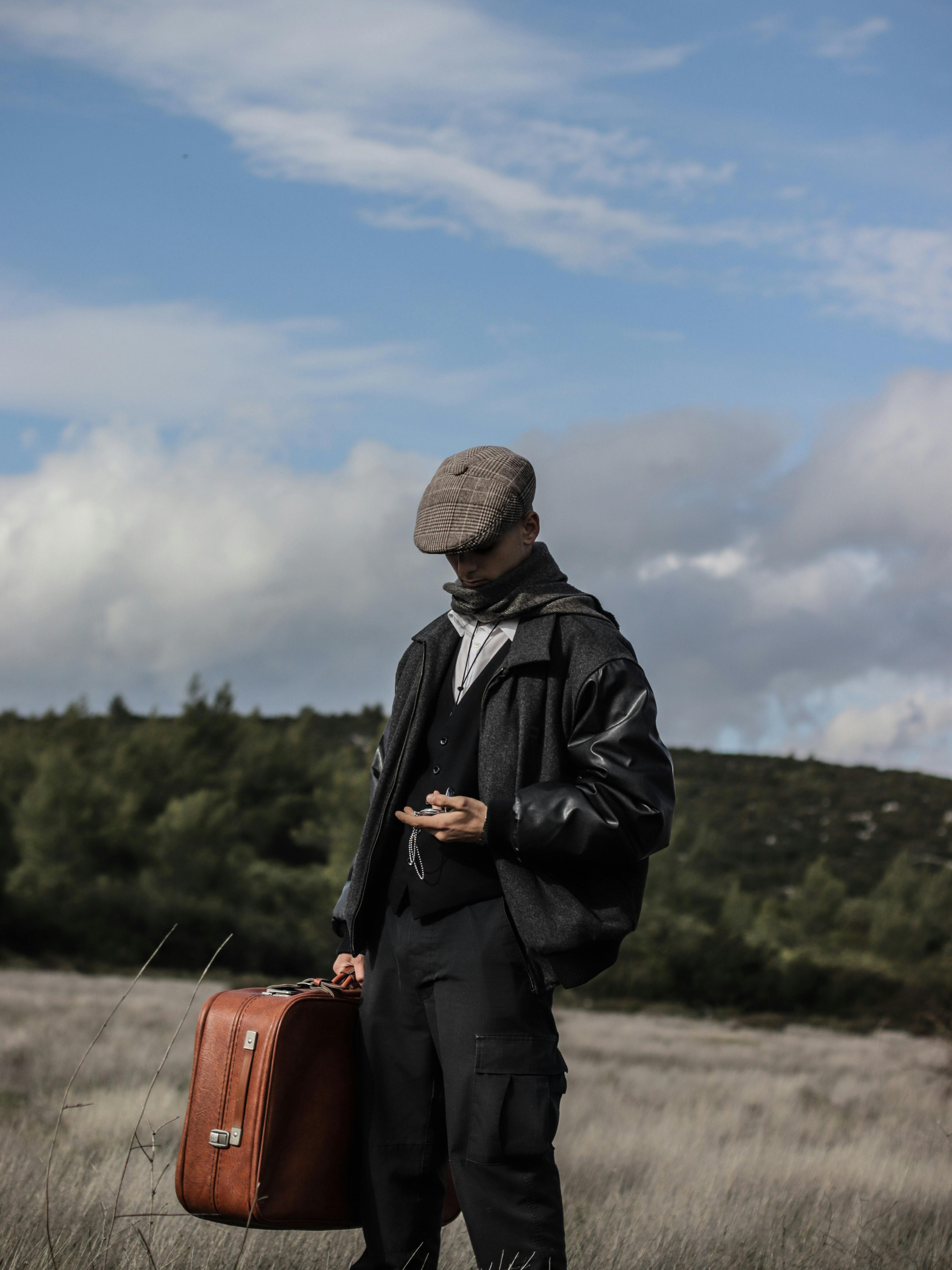 Man Standing in a Field with a Suitcase · Free Stock Photo