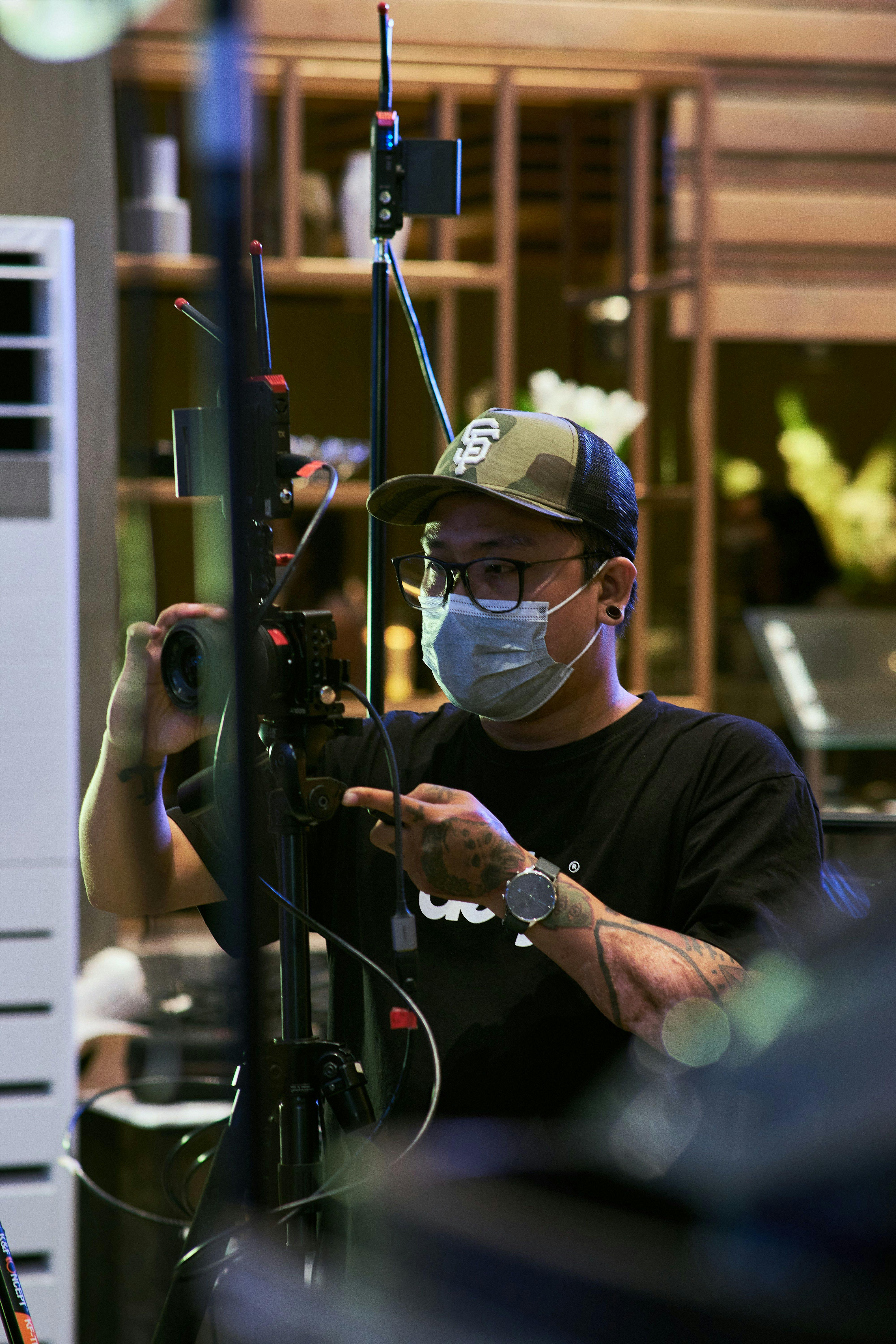 Man Wearing Cap and Facemask Holding a Camera · Free Stock Photo