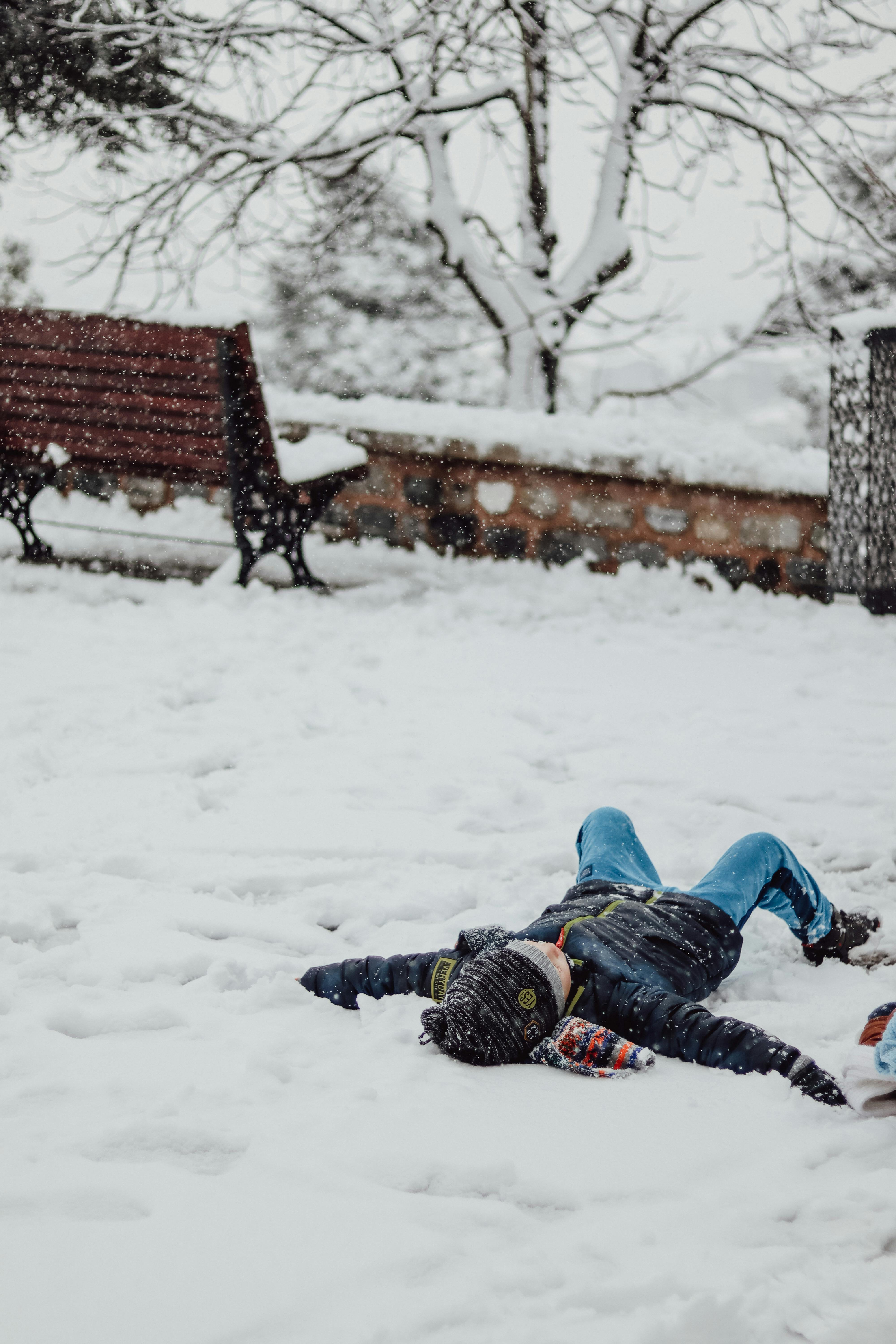 A Person in Winter Clothes Lying on Snow Covered Ground · Free Stock Photo