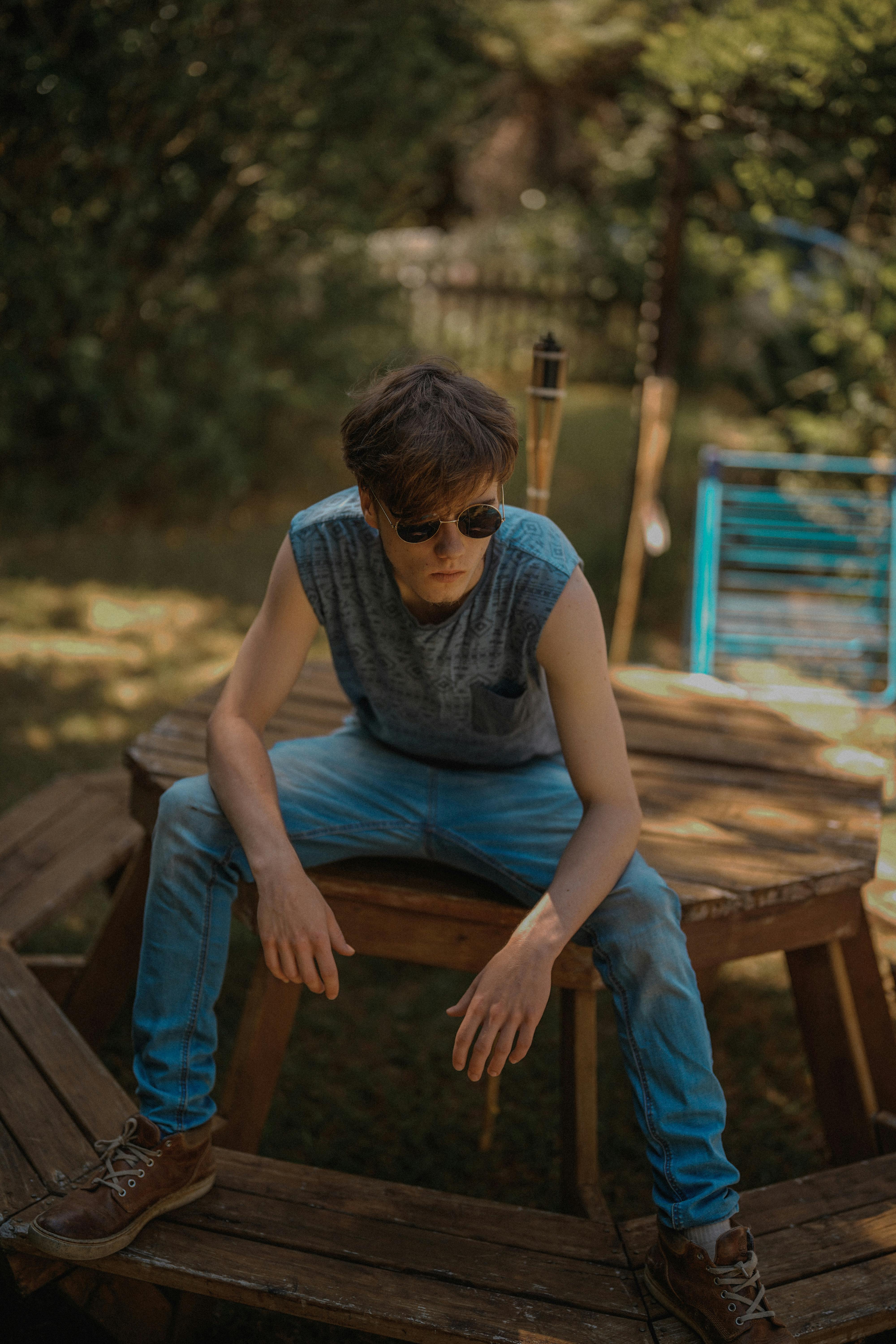 A Young Man Sitting on Wooden Table · Free Stock Photo