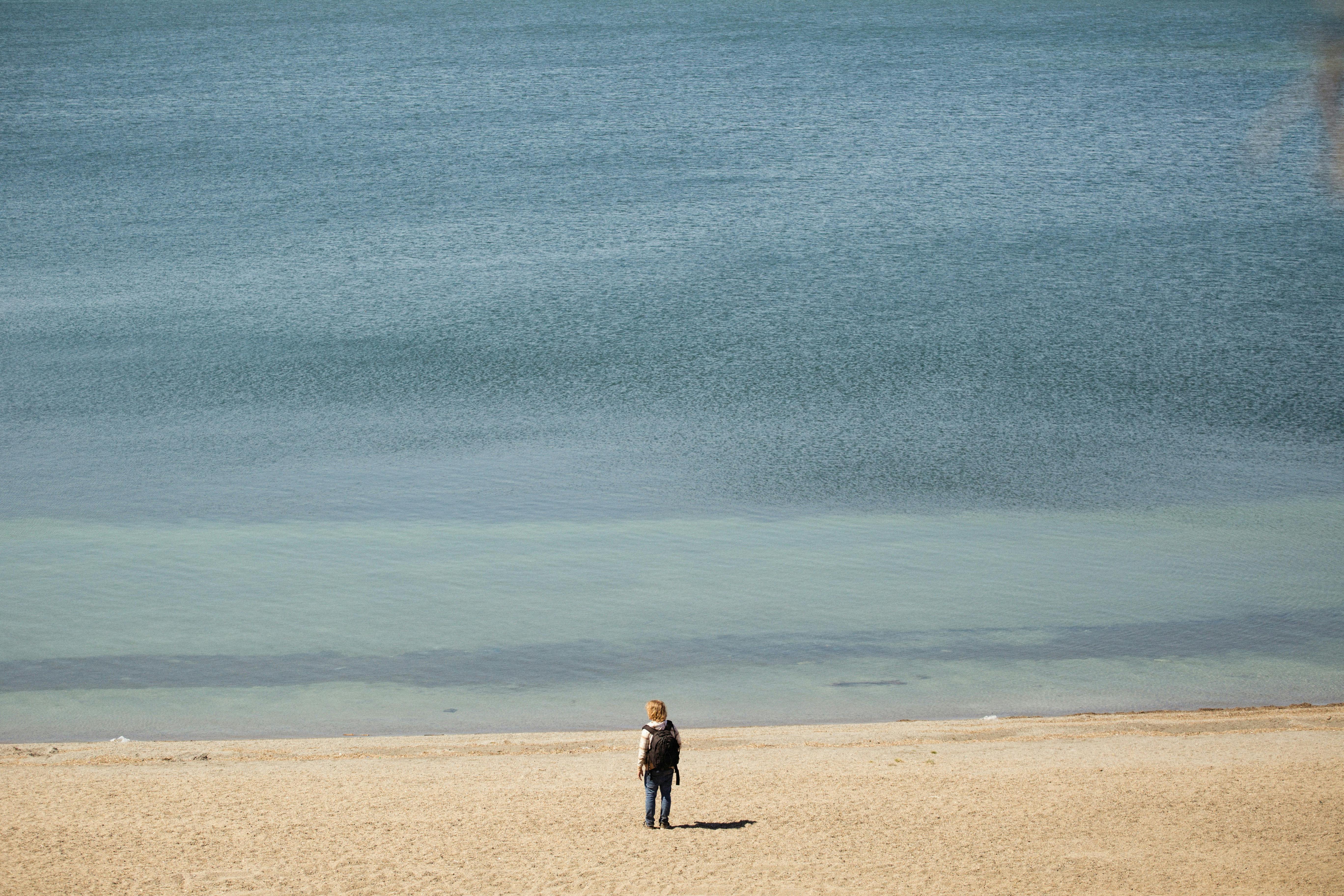 Back View of a Kid Standing Alone at the Beach · Free Stock Photo