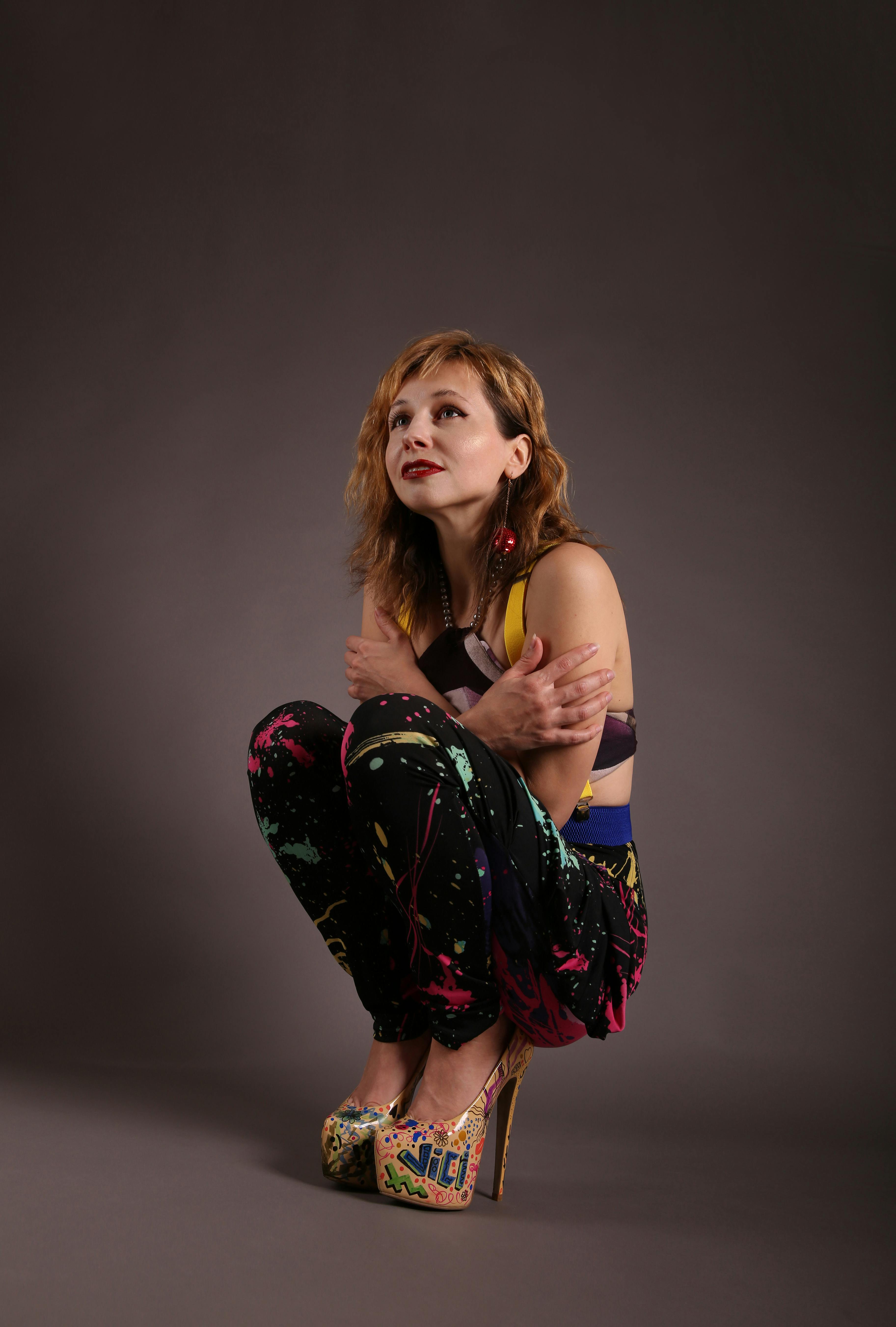 Female Model Crouching in Black Jacket and Black Heels · Free Stock Photo