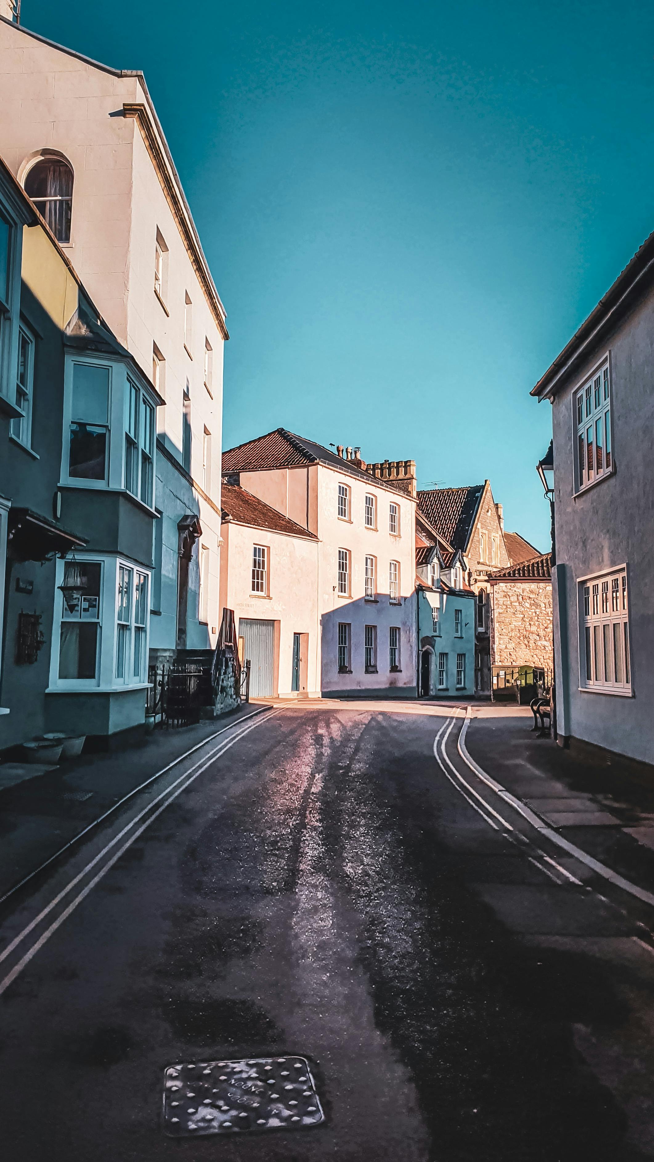 Empty Road Between Concrete Houses Under Blue Sky · Free Stock Photo