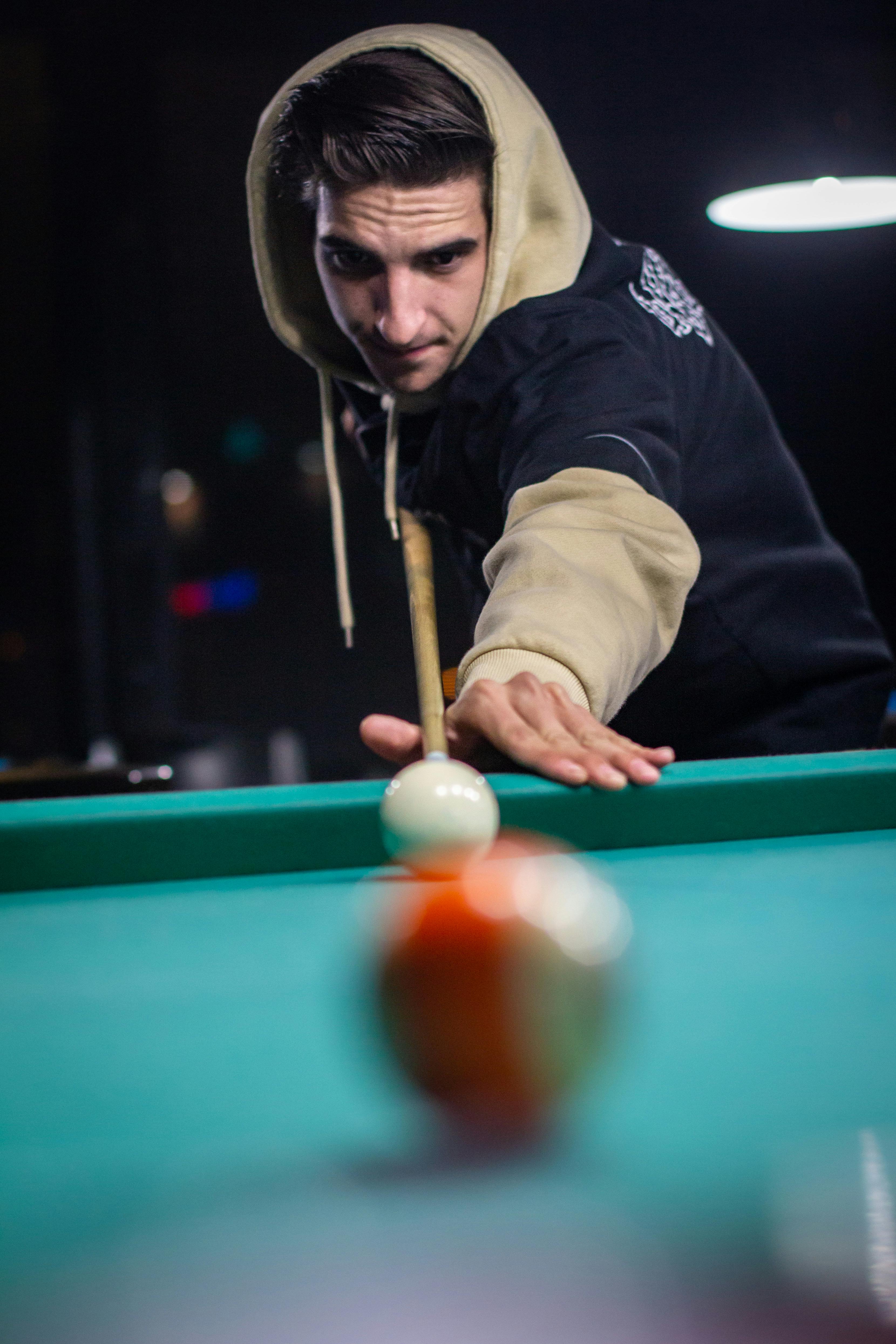 A Man Sitting on the Billiard Table while Holding a Cue Stick · Free ...