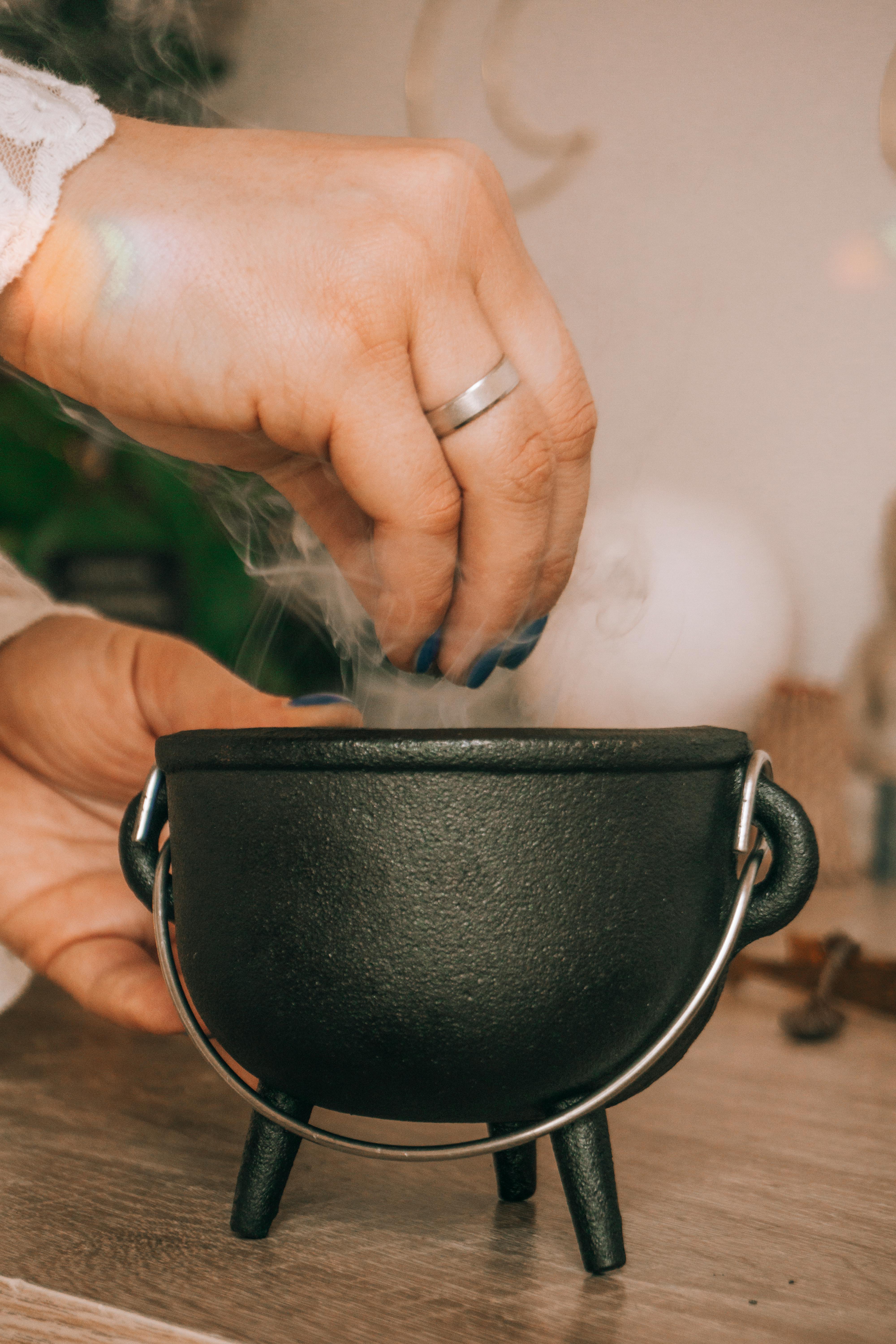 Woman Putting Herbs in Small Iron Cauldron · Free Stock Photo