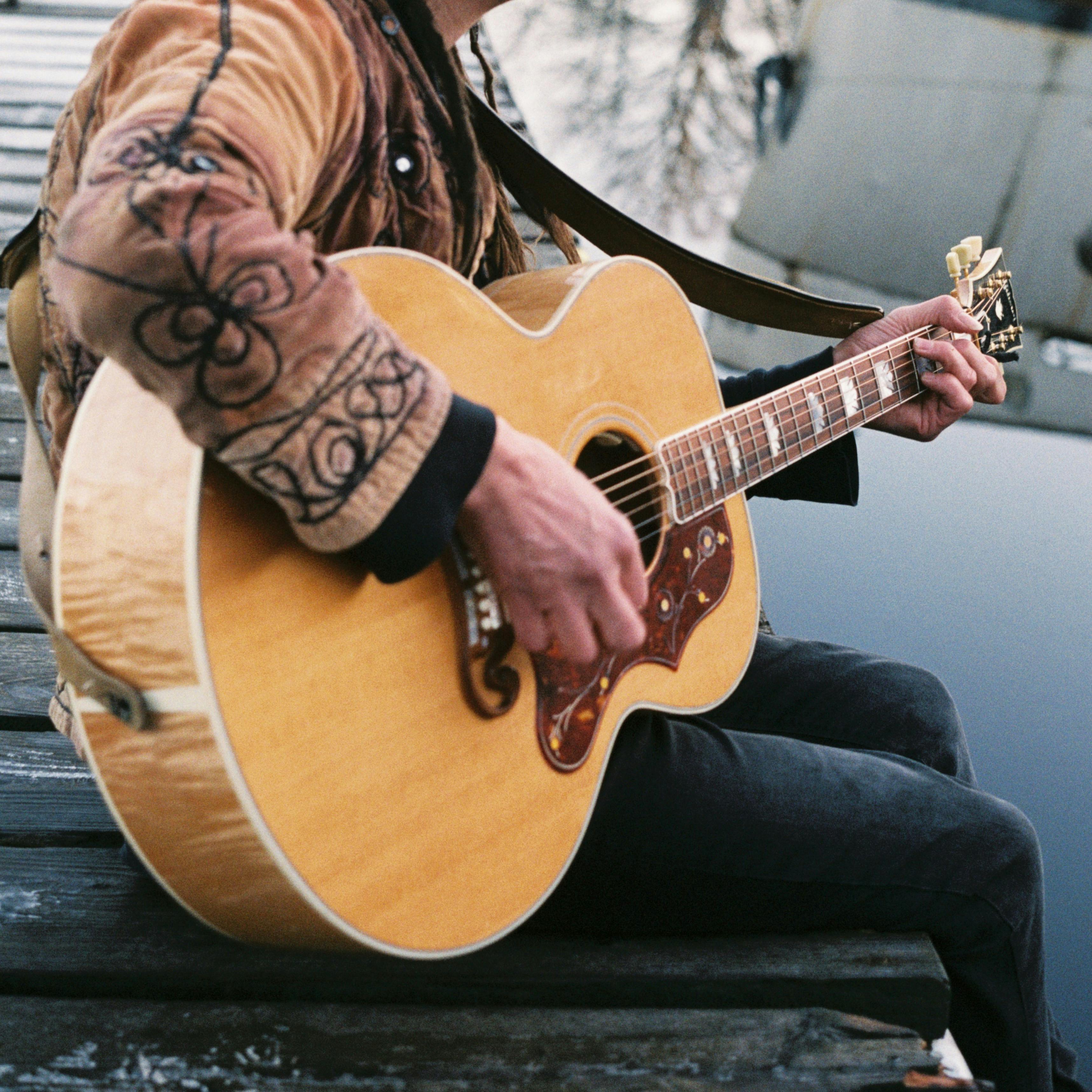Close-Up Shot of a Person Playing Acoustic Guitar · Free Stock Photo
